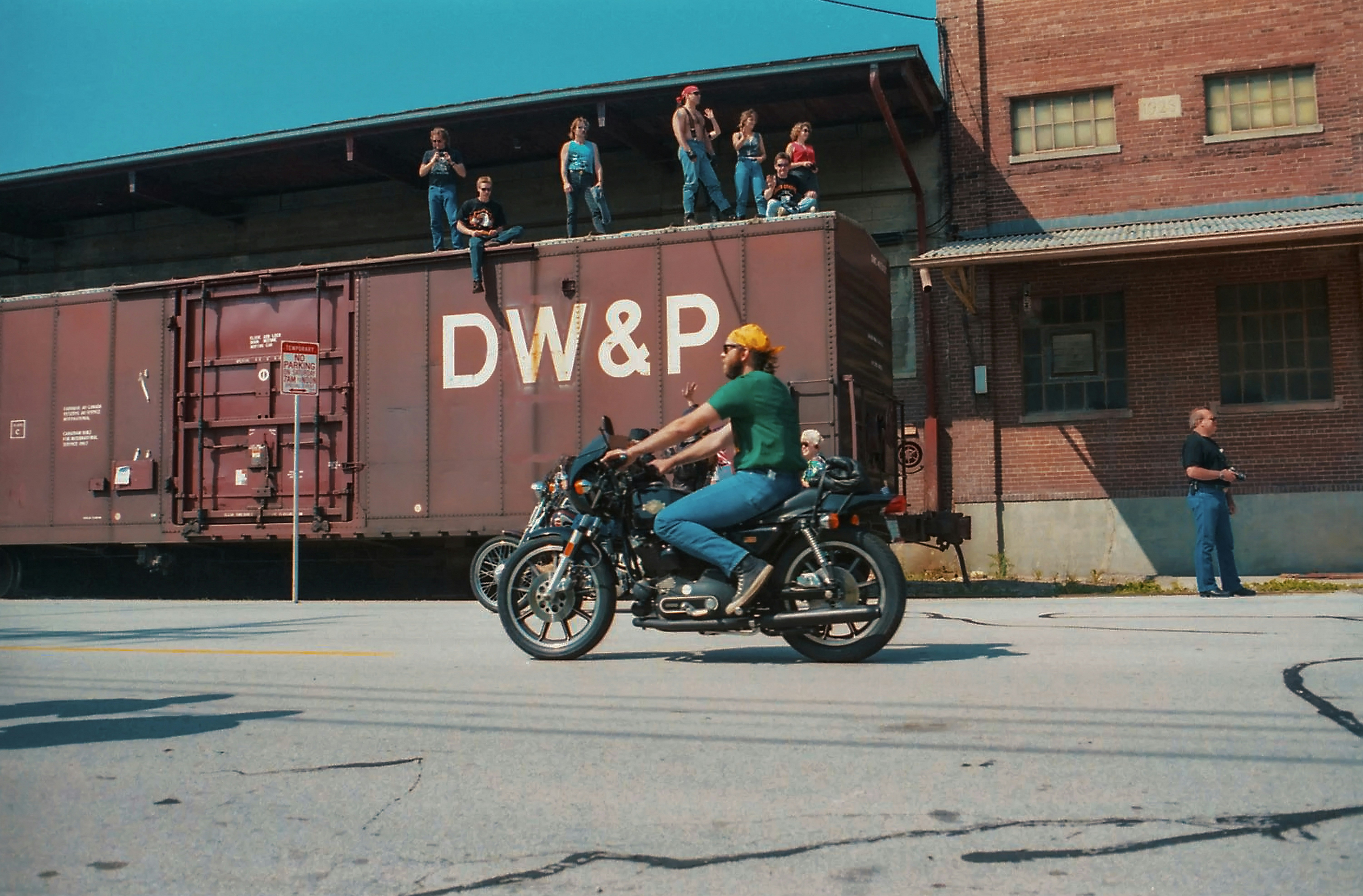 A man riding a motorcycle down a street next to a train photo – Free ...