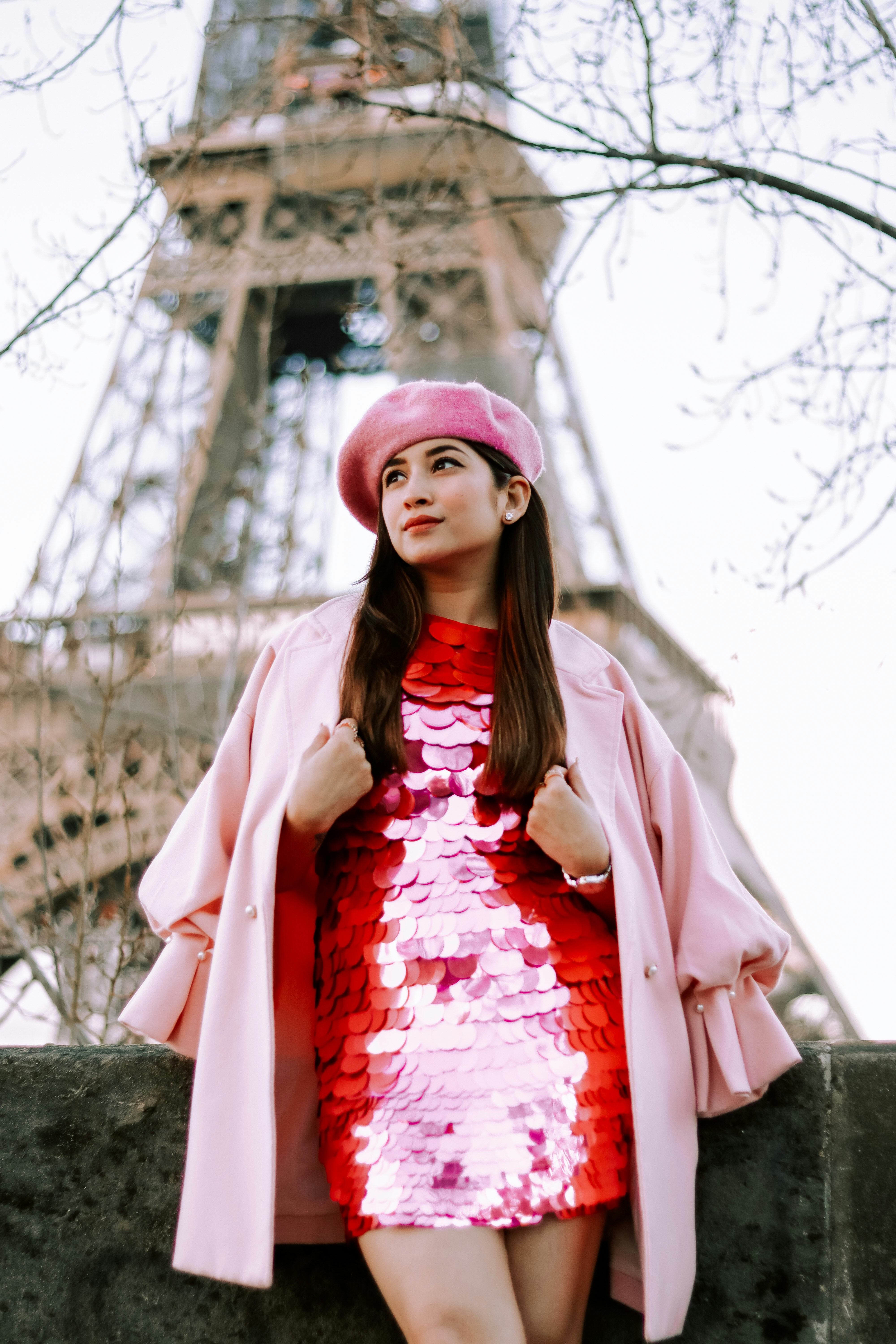 Sequins Under Paris Sky: A Pink-Cloaked Portrait with the Eiffel Tower in Soft Focus