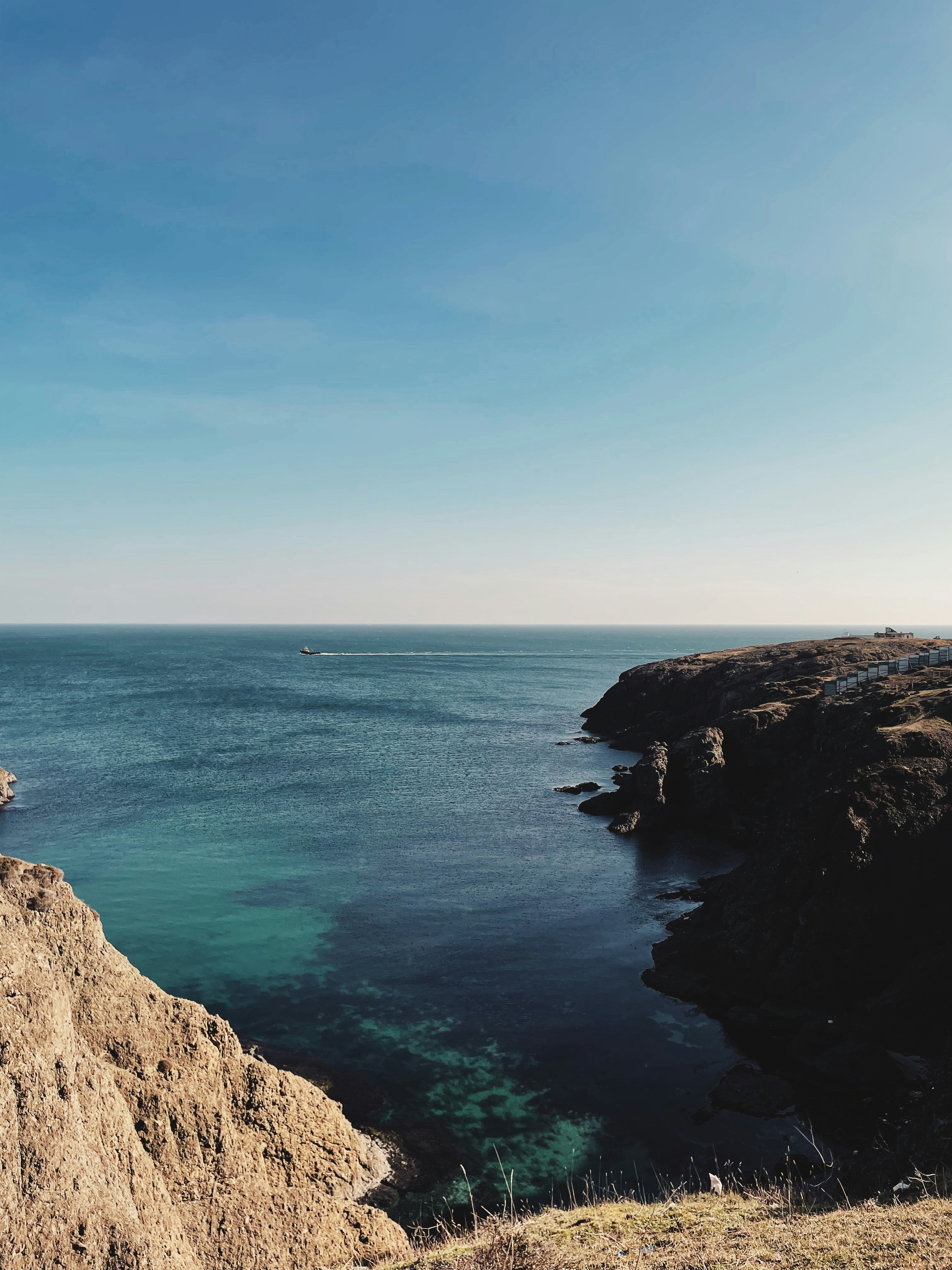 A person standing on a cliff overlooking the ocean photo – Free Sky ...