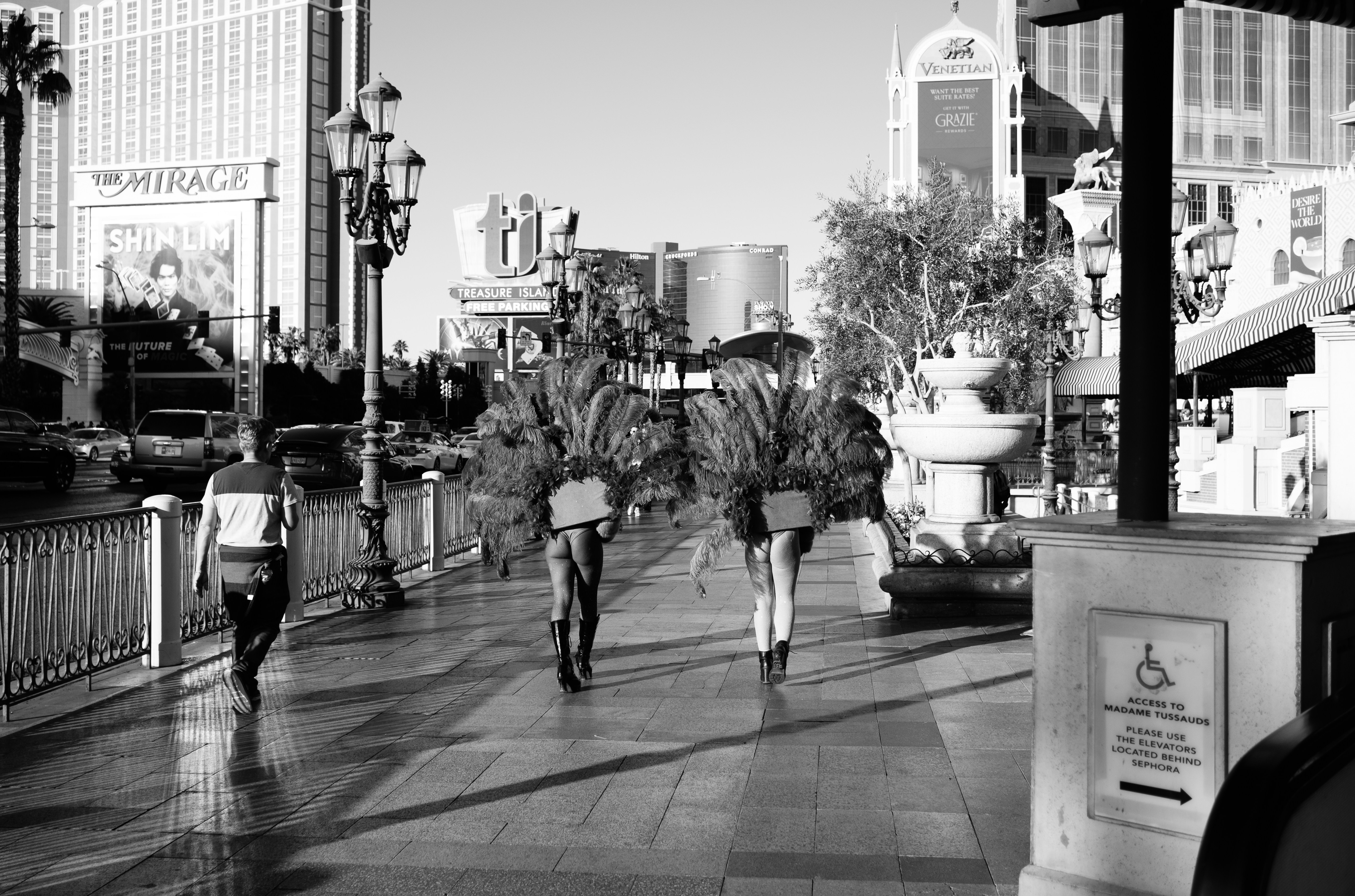 A couple of people walking down a sidewalk next to tall buildings photo ...