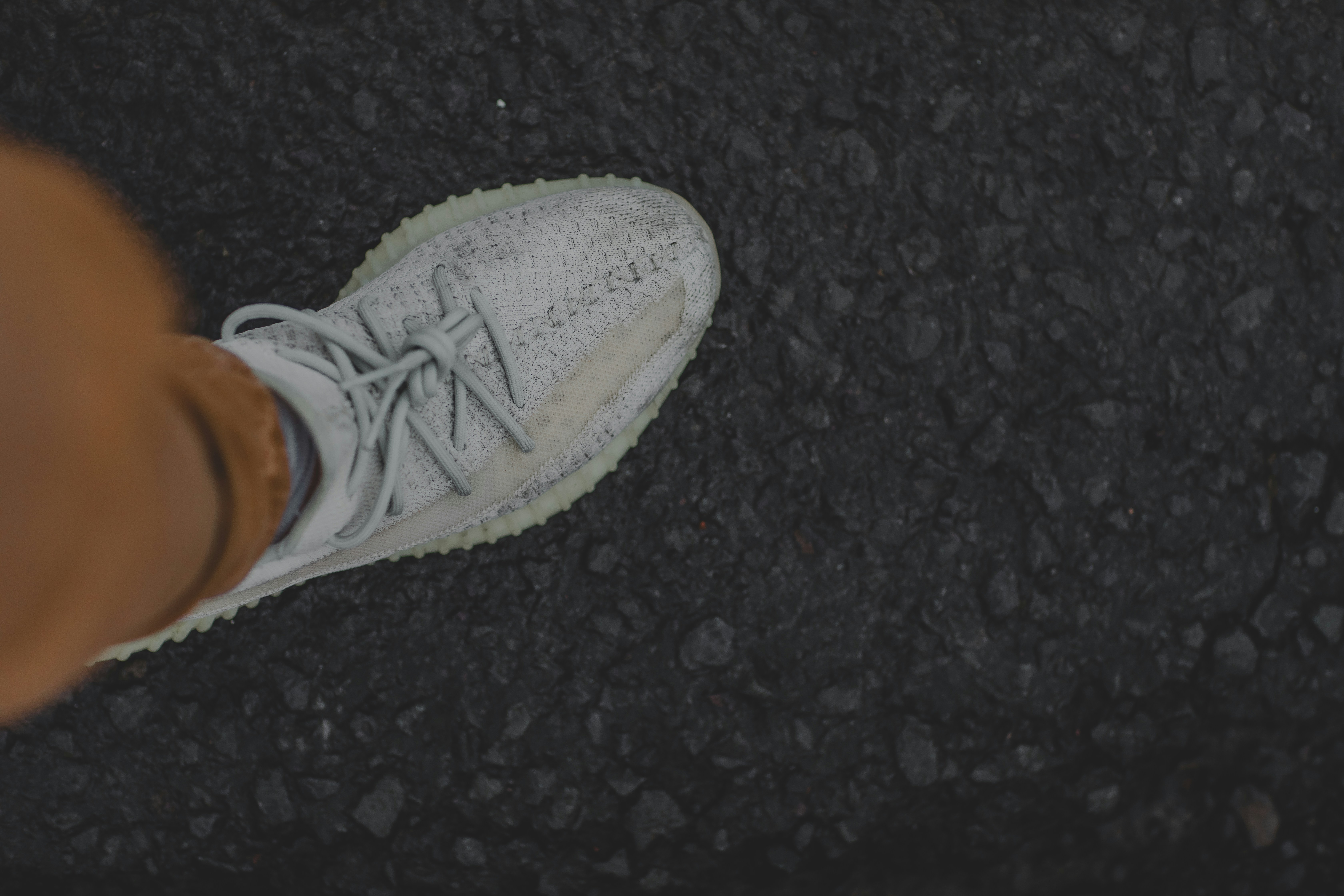 Footfall on Blacktop: A White Knit Sneaker in Sharp Focus