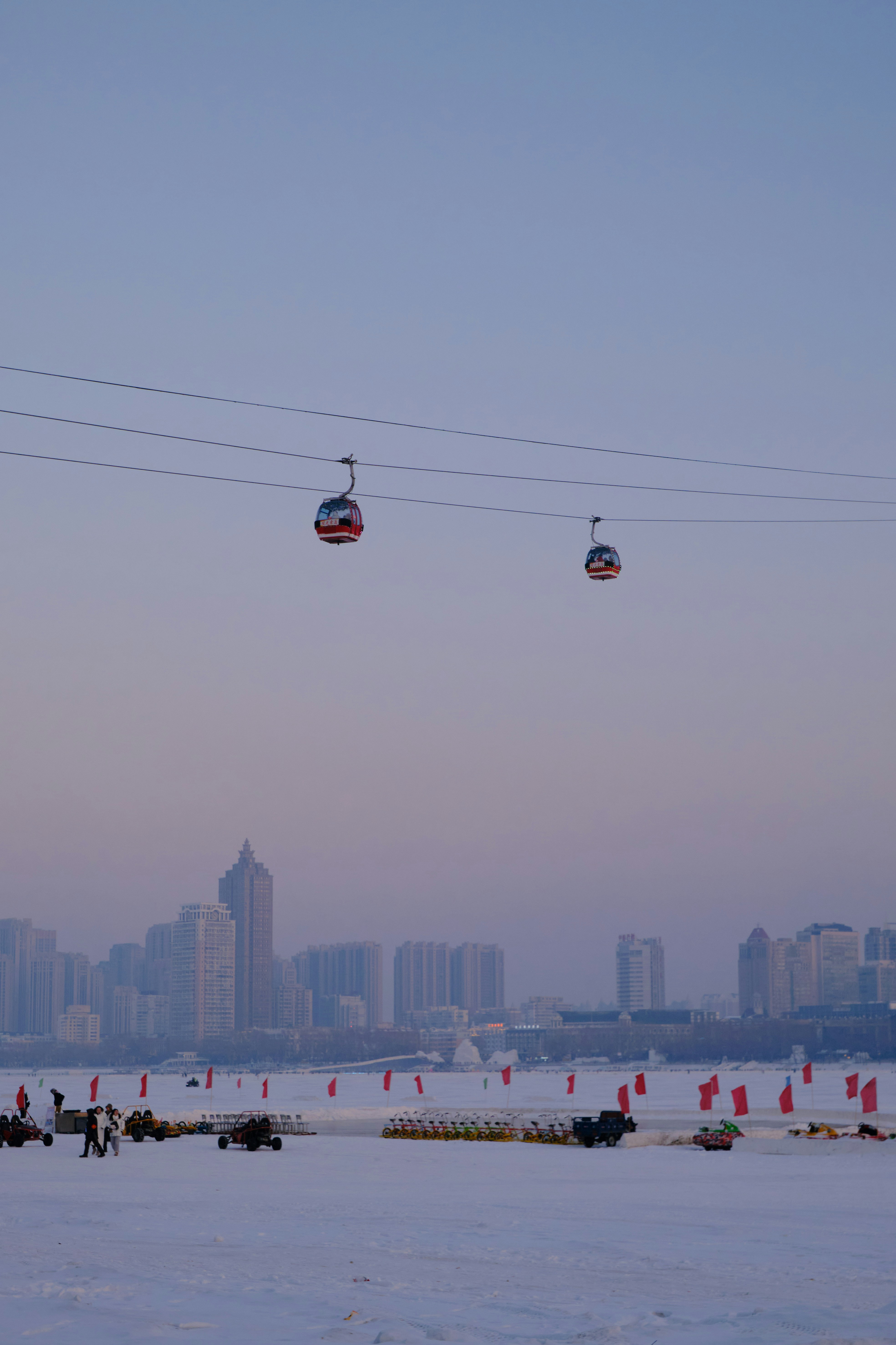 Pastel Dusk Aglow: Twin Cable Cars Above a Snowbound City