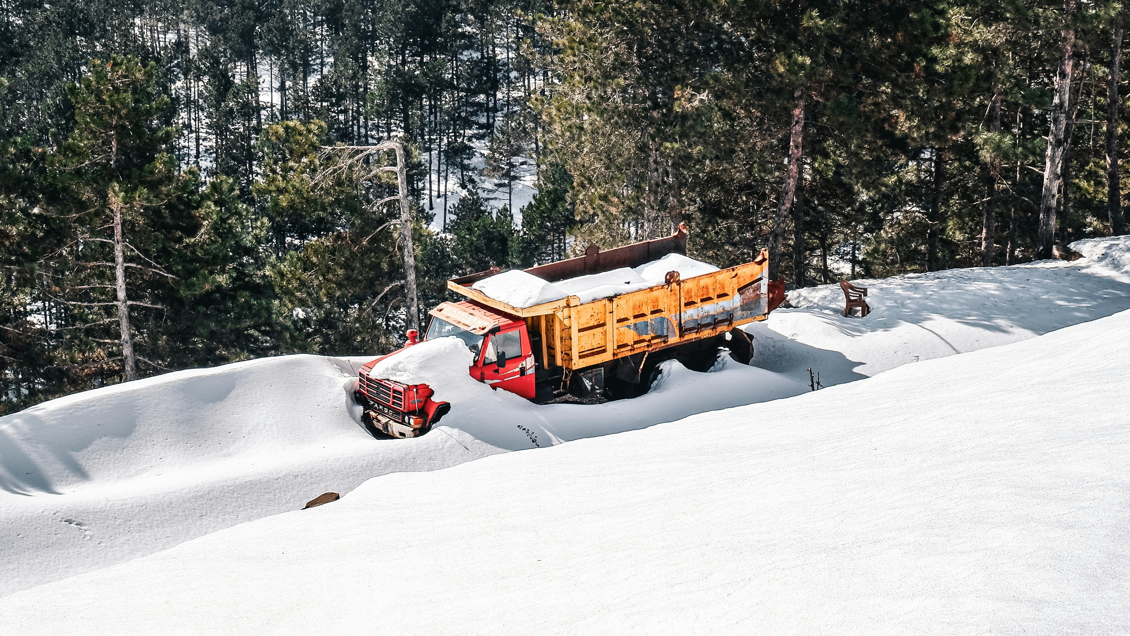 a red truck driving down a snow covered slope