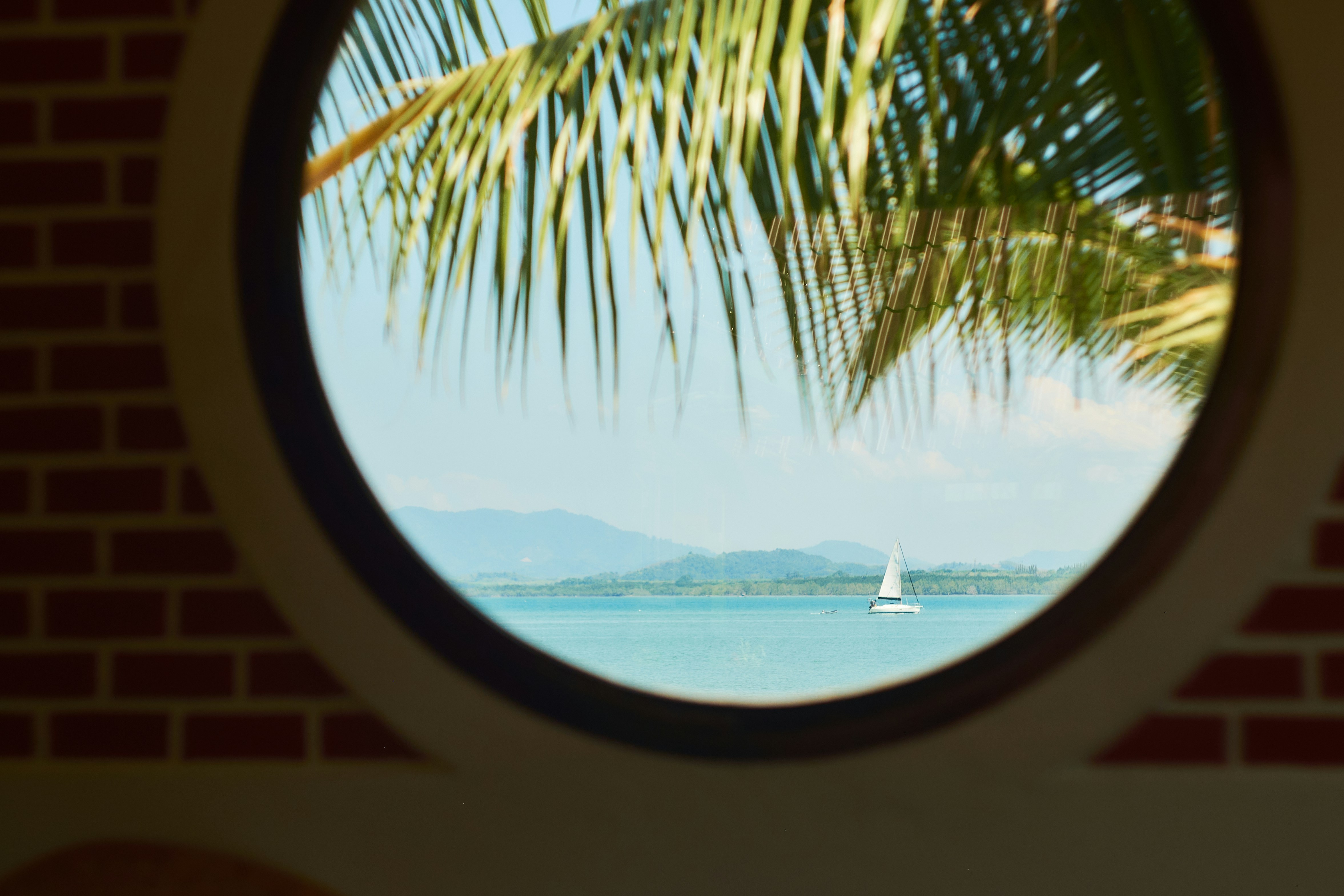 A view of a sailboat through a round window photo – Free Boat Image on ...