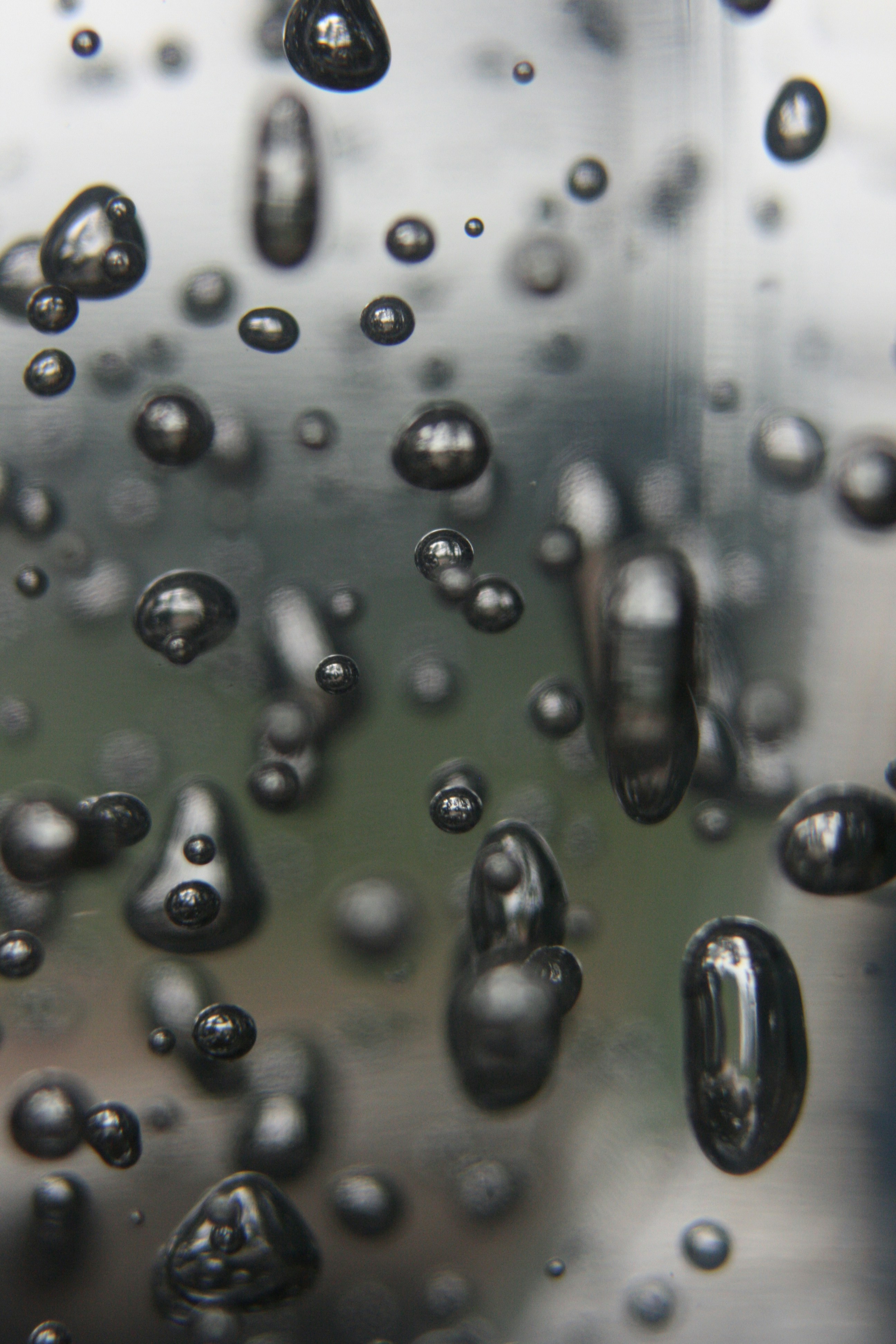 Close-up of various water droplets suspended in mid-air, creating a dynamic interplay of shapes and reflections against a blurred background.