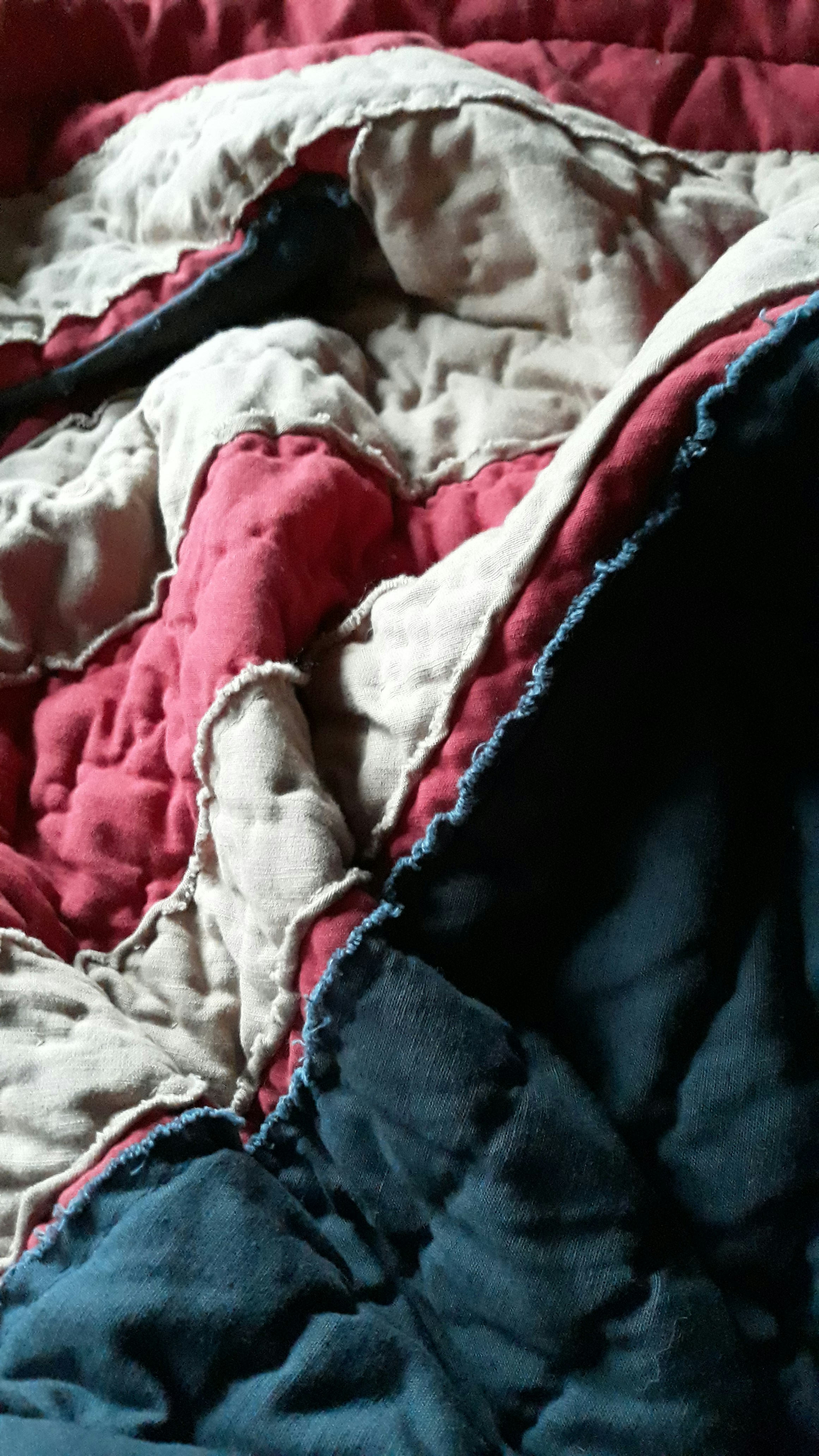 Close-up of a quilt showcasing intricate textures and rich colors, emphasizing the interplay of fabric layers and patterns.