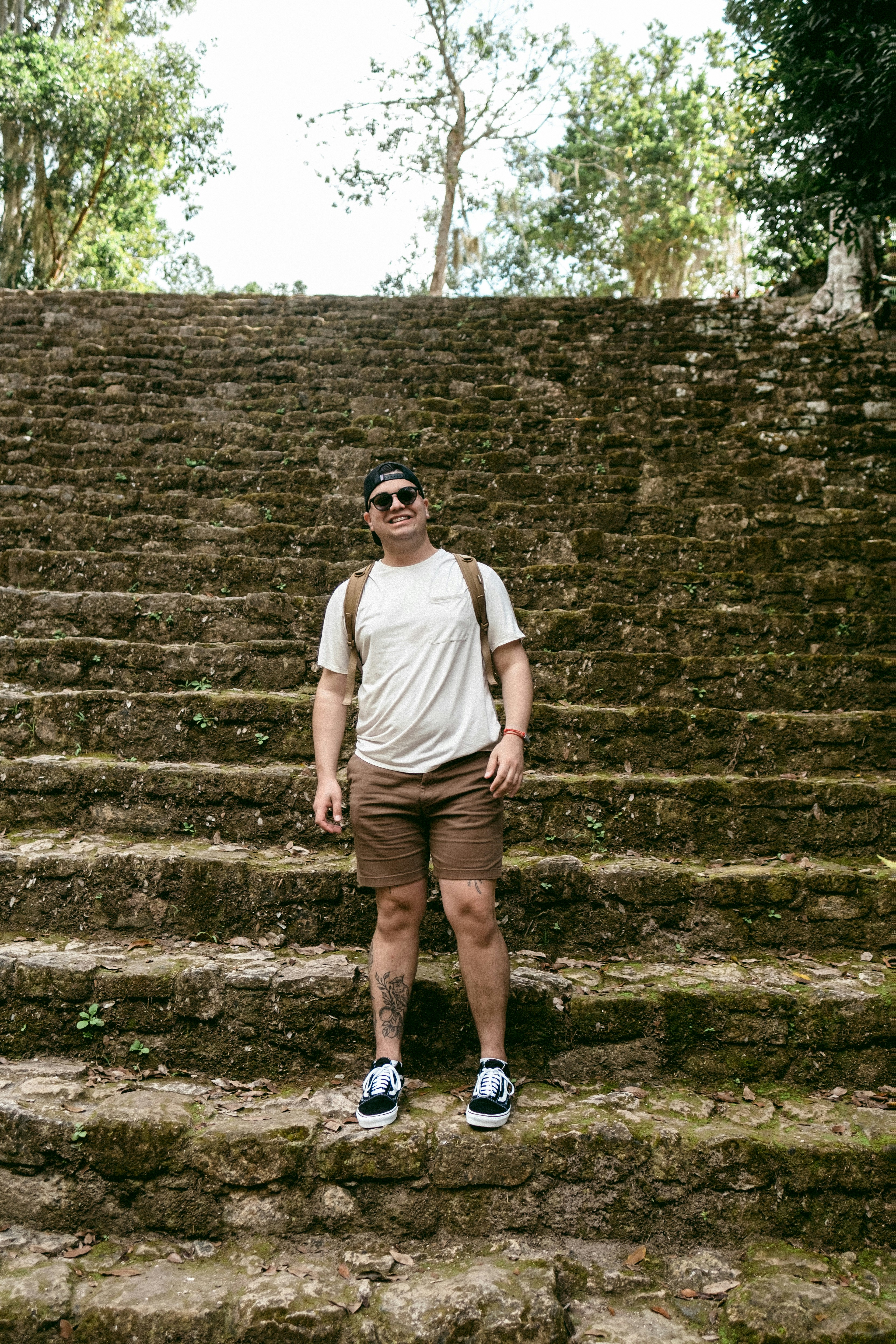 Traveler on mossy steps: casual portrait beneath a stone staircase