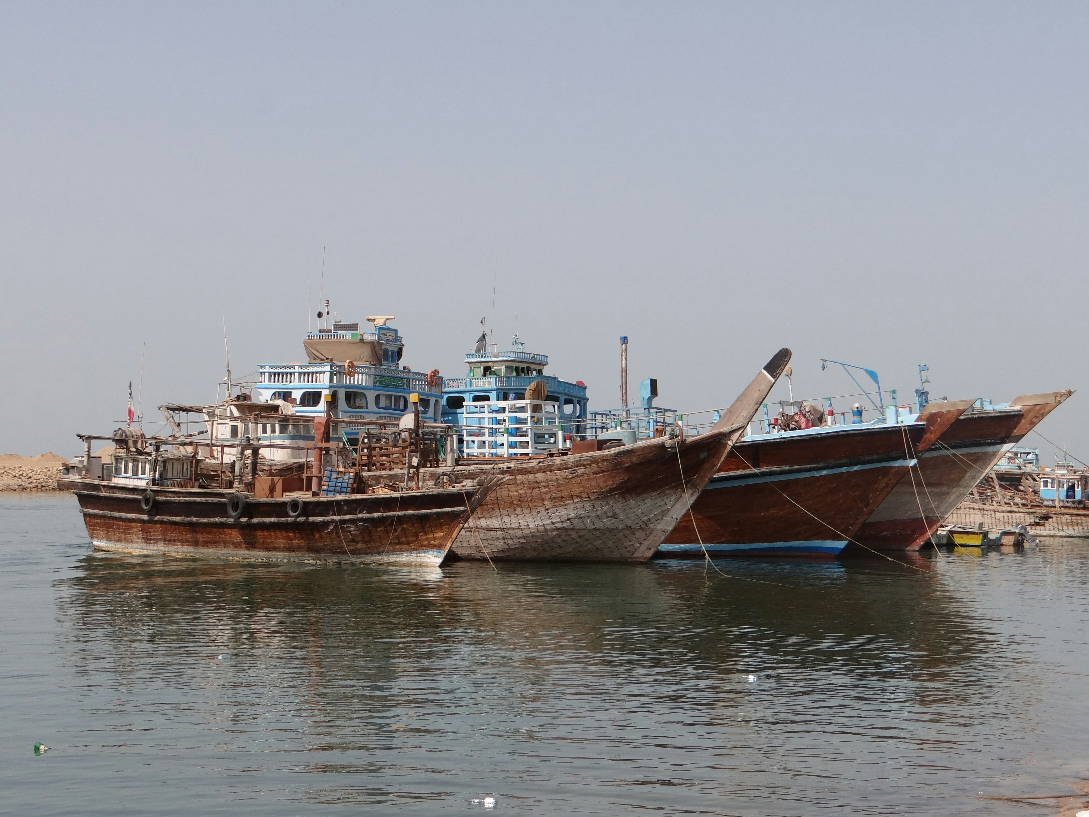 Wooden fishing boats docked in calm waters under a clear sky.