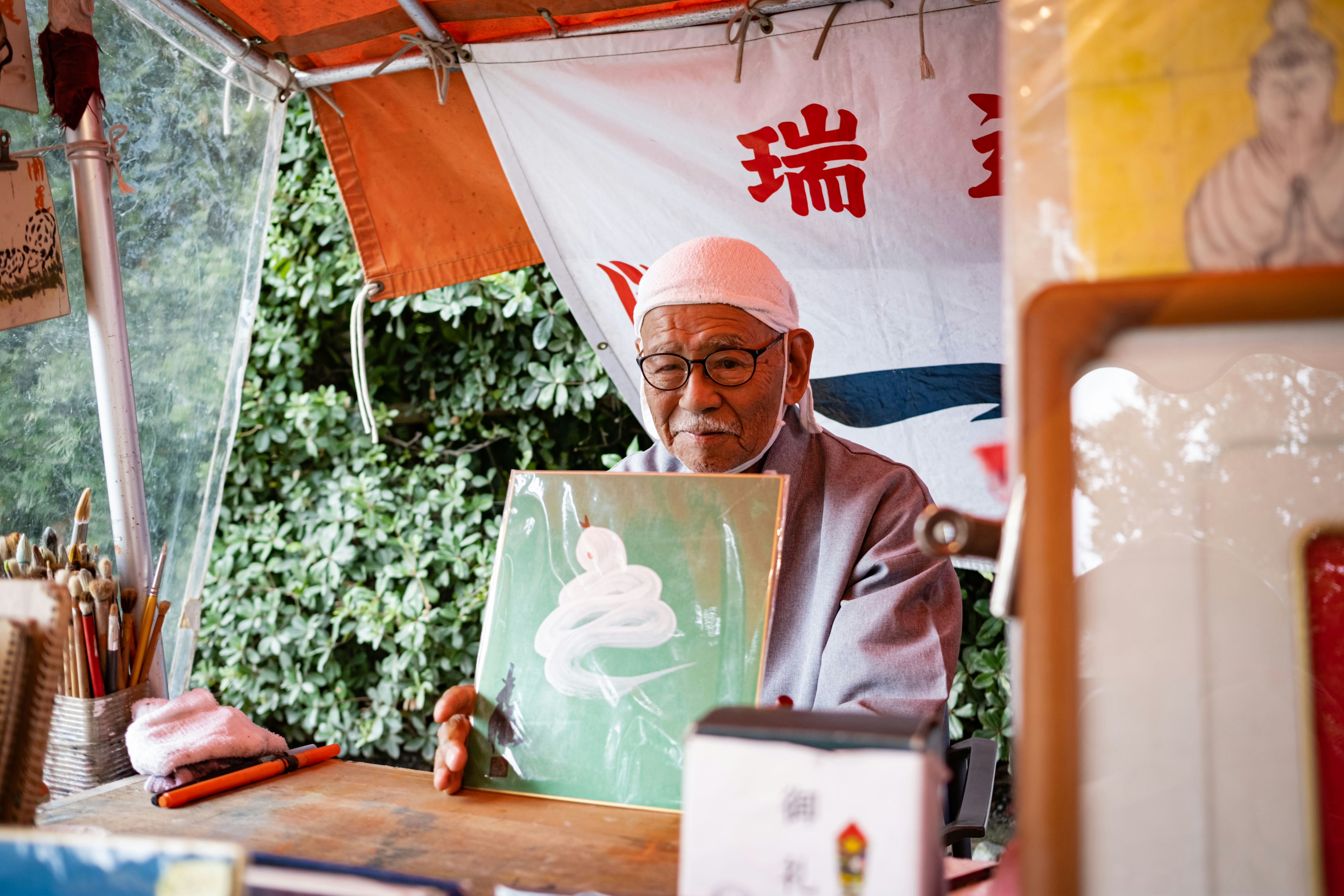 a man sitting at a table with a painting in front of him