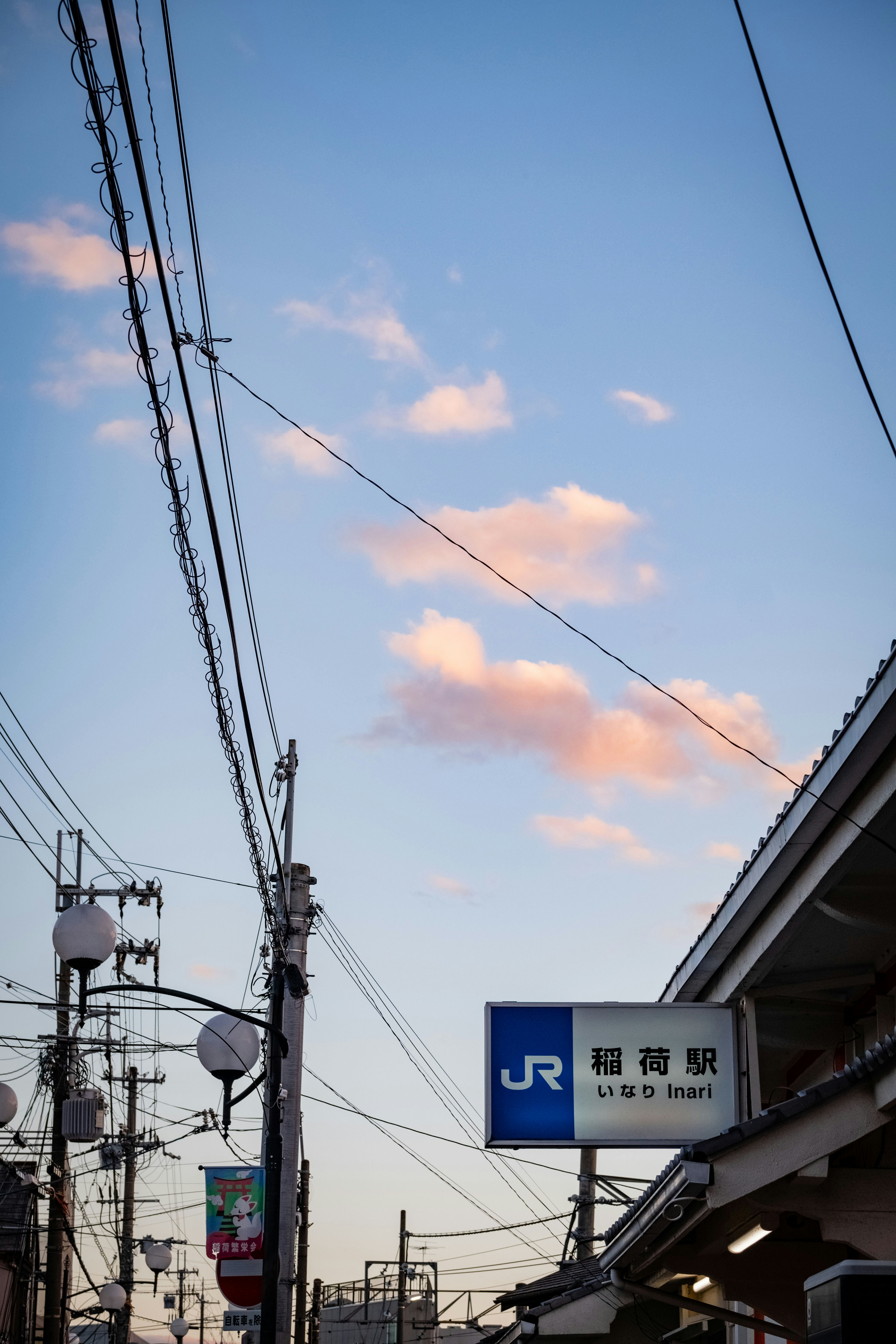Inari Station Sign: A Street Scene Threaded by Wires at Dusk