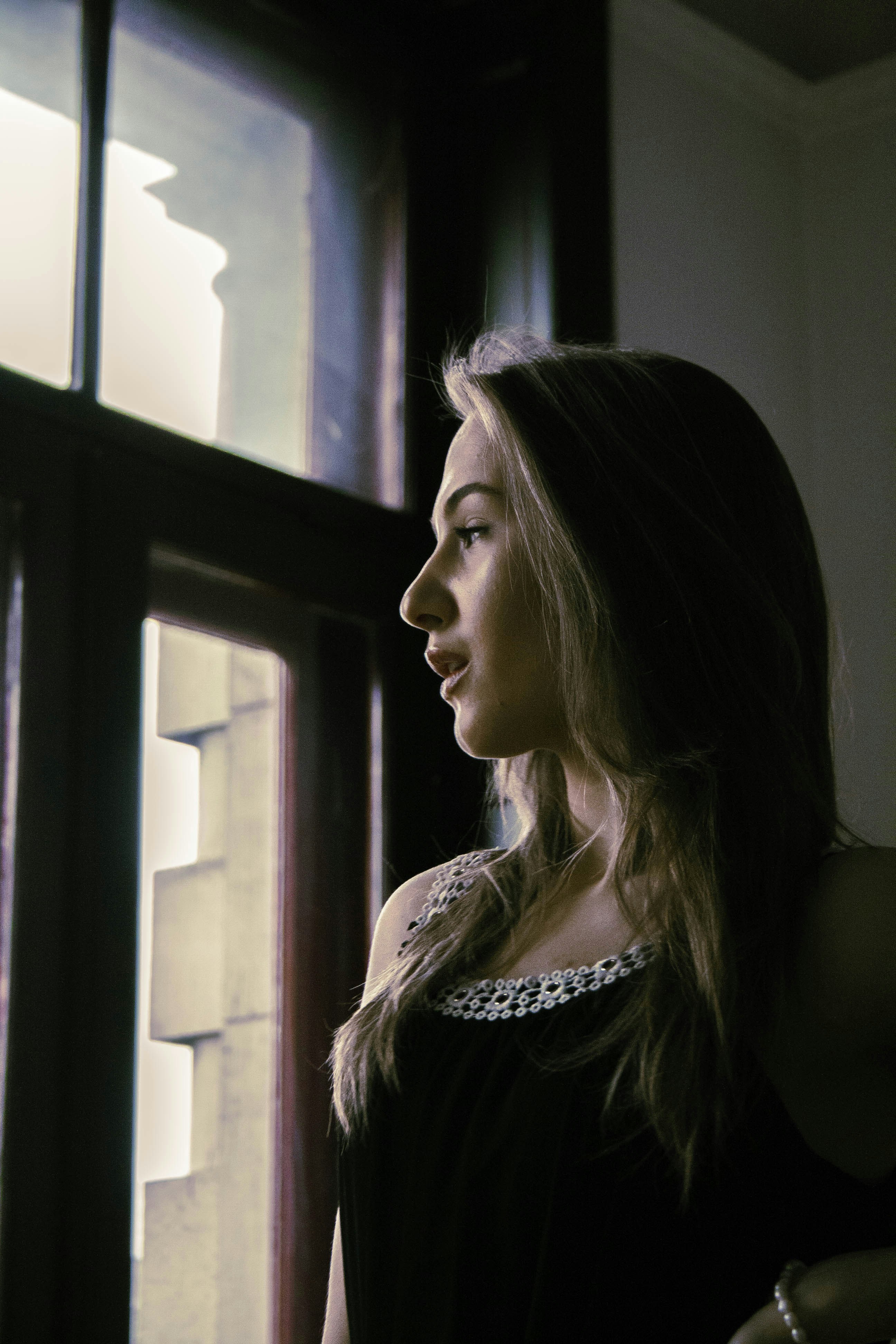 A woman standing in front of a window looking out photo – Free Portrait ...