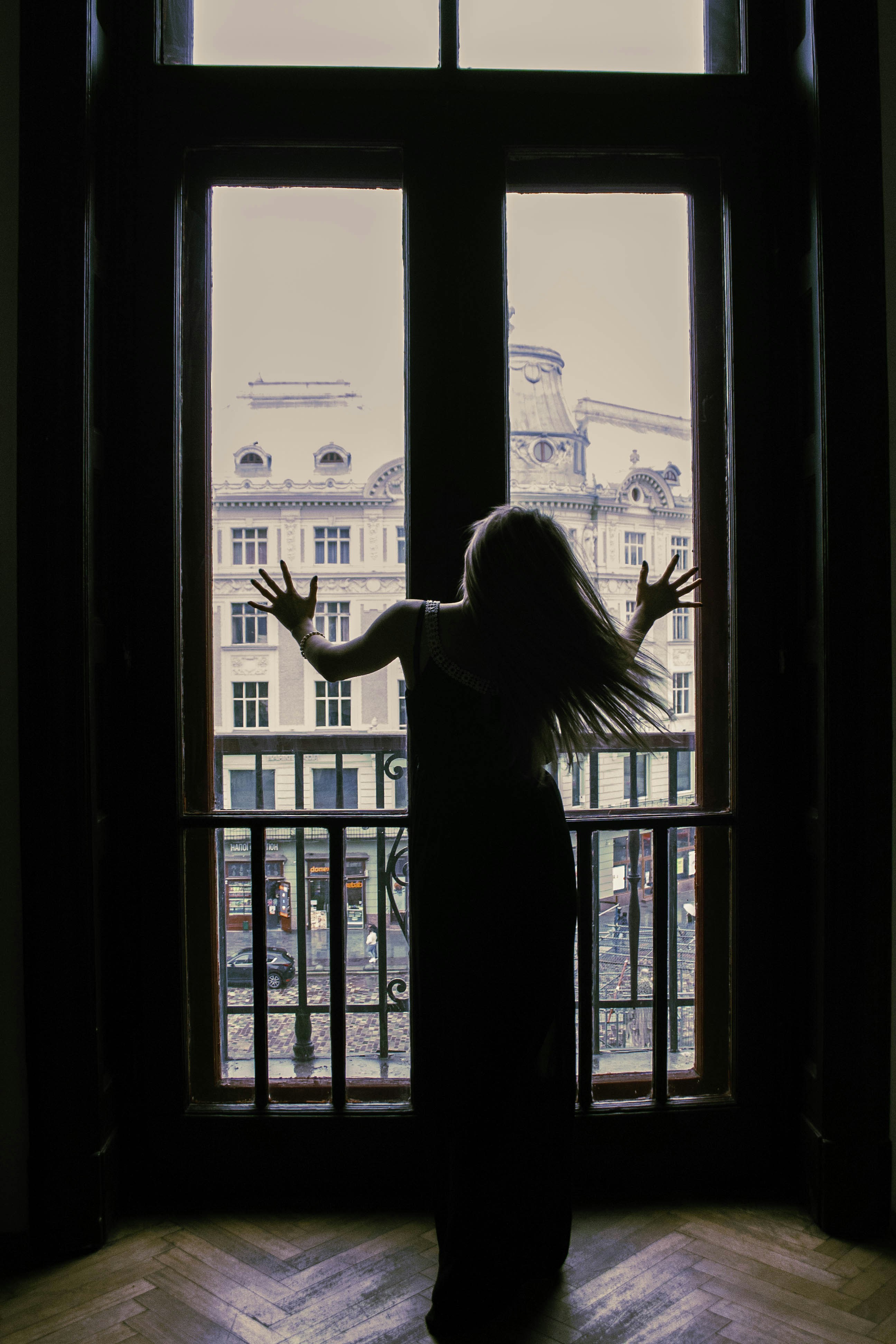 Silhouette at the Window: A City Dive into Light and Shadow