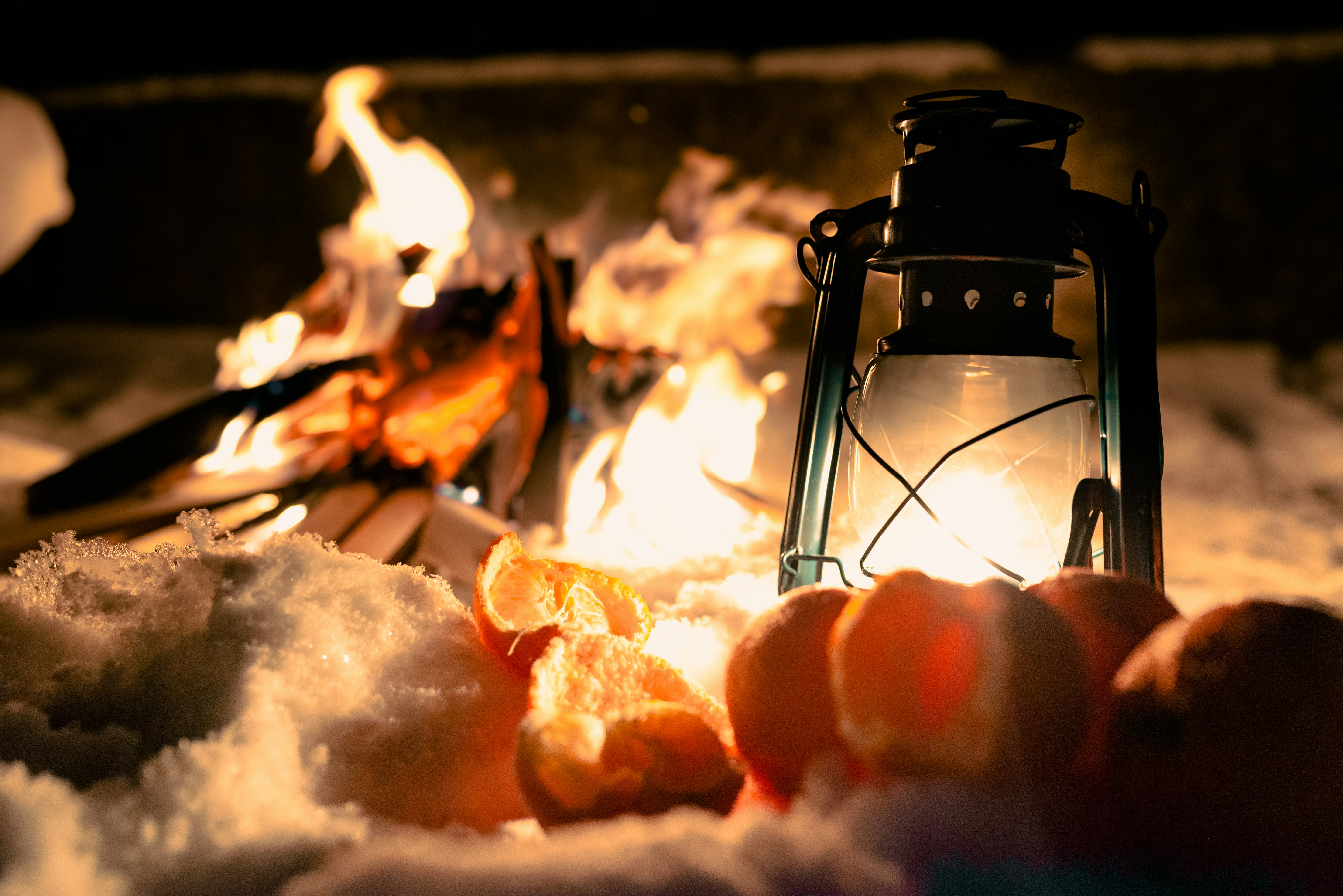 a lantern sitting on top of a pile of snow next to a fire