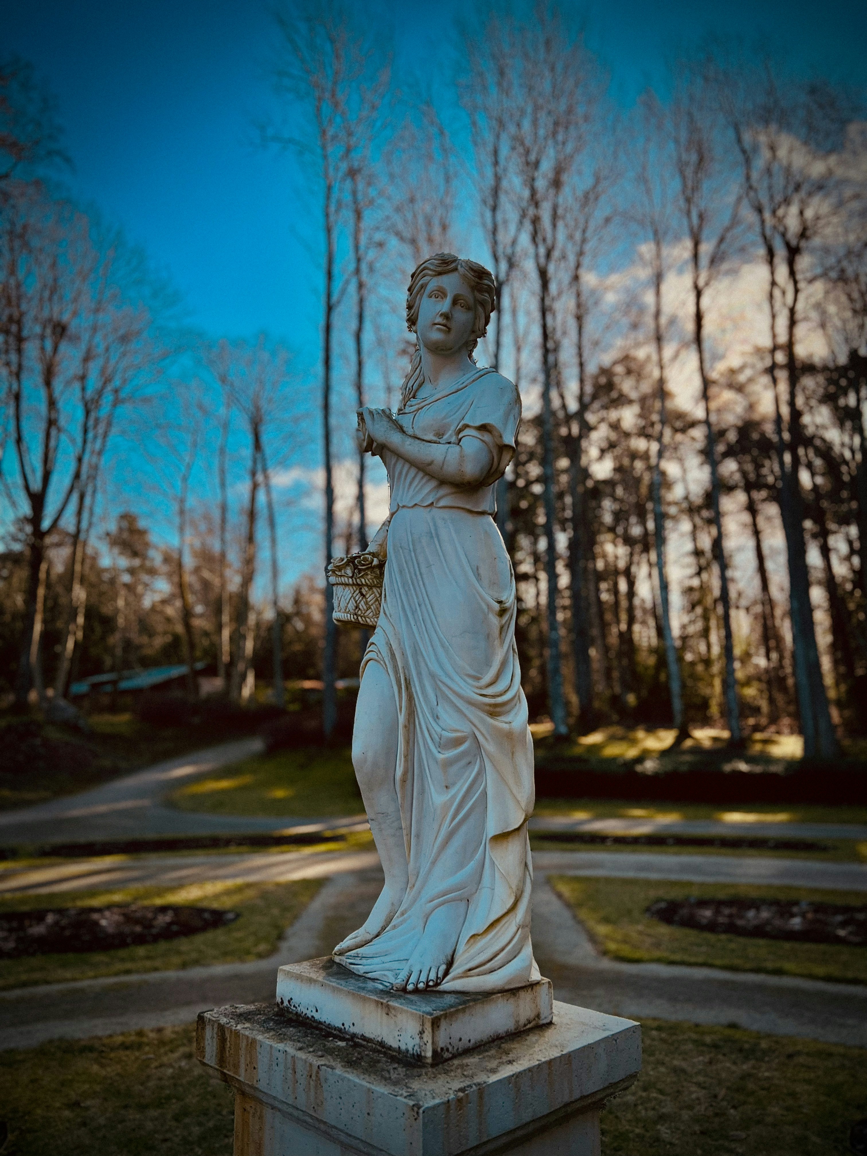 Draped Marble Statue in a Quiet Park Under a Clear Azure Sky