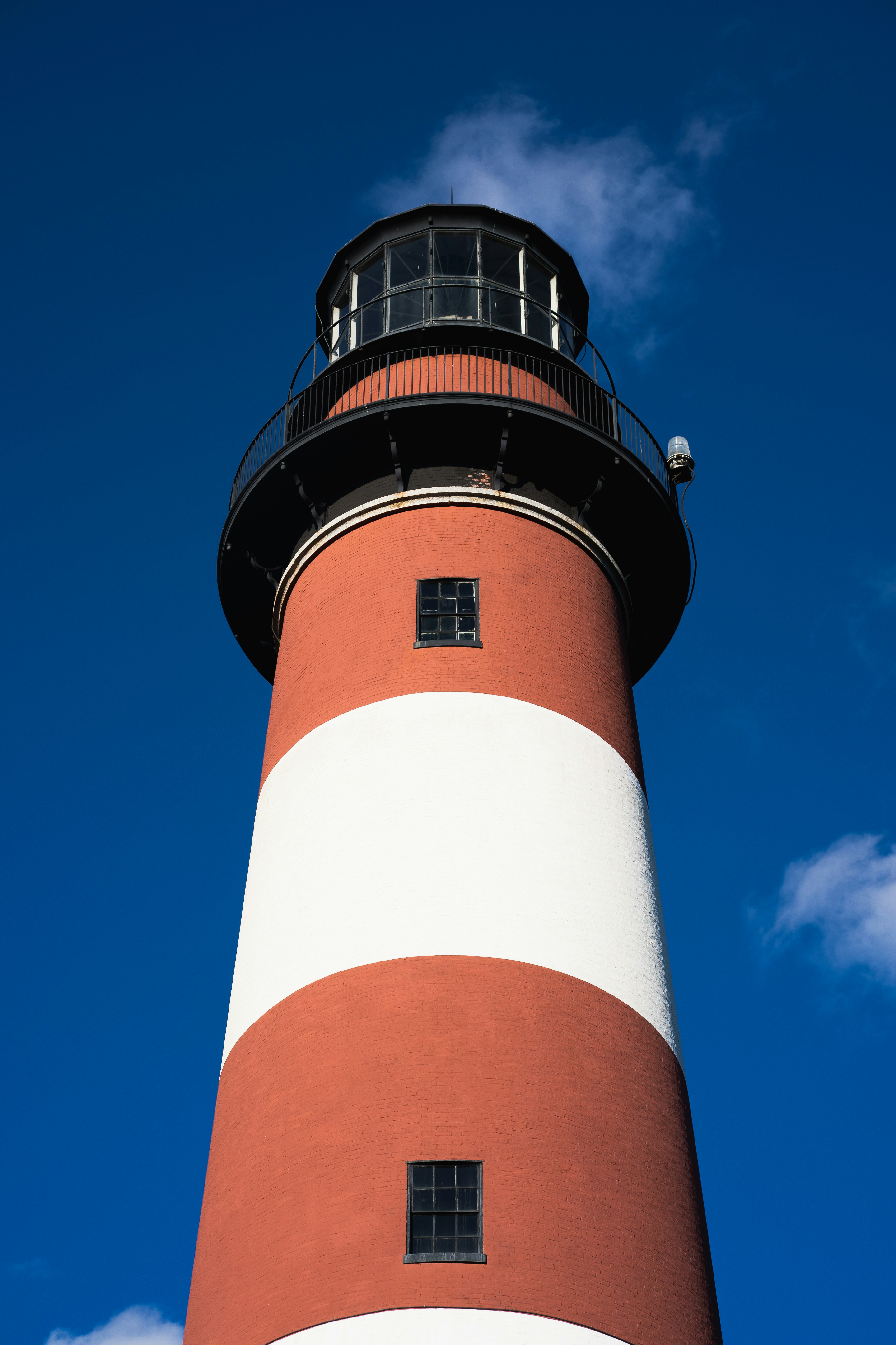 A red and white lighthouse with a blue sky in the background photo ...