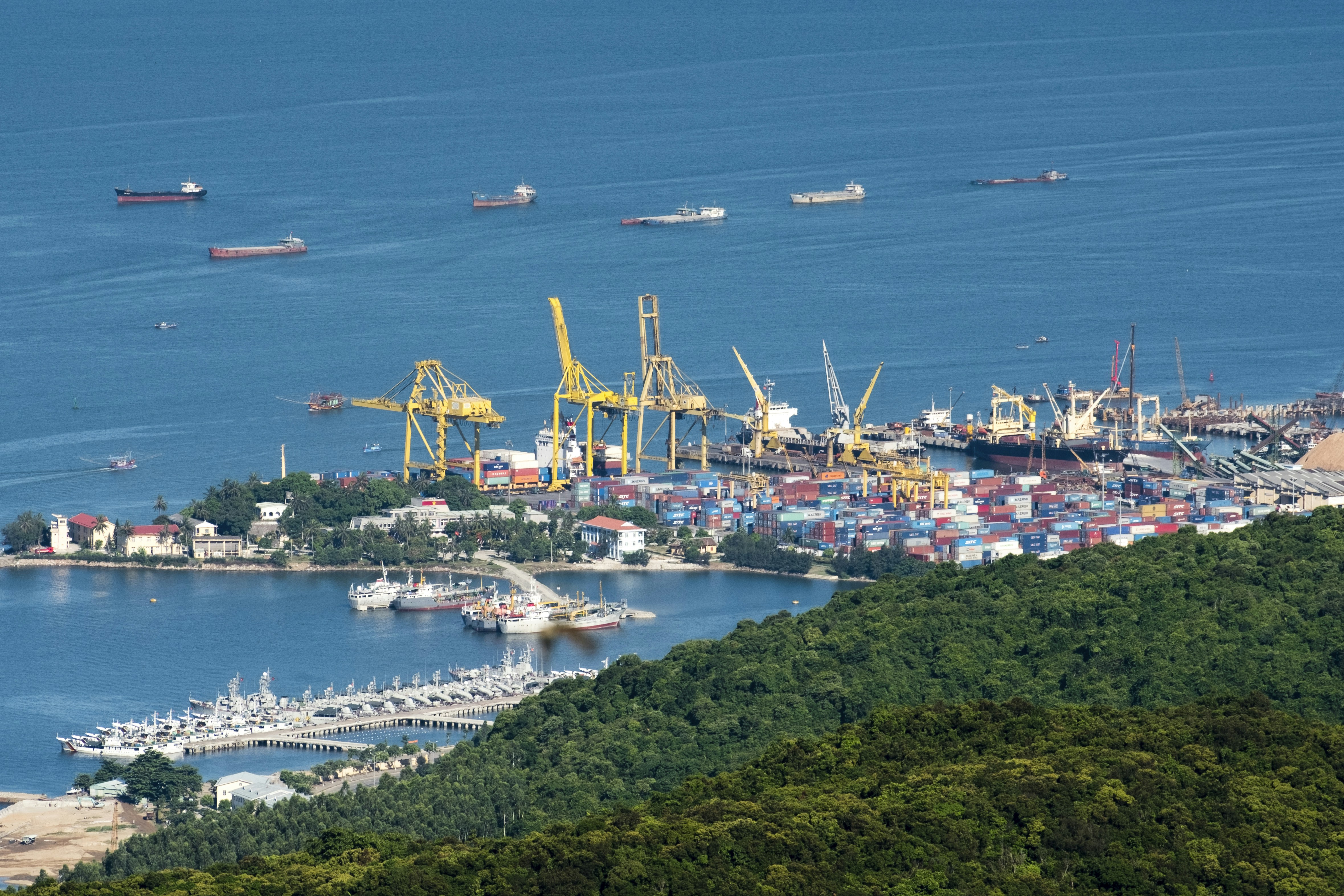 Foto Un puerto lleno de muchos barcos junto a una exuberante ladera ...