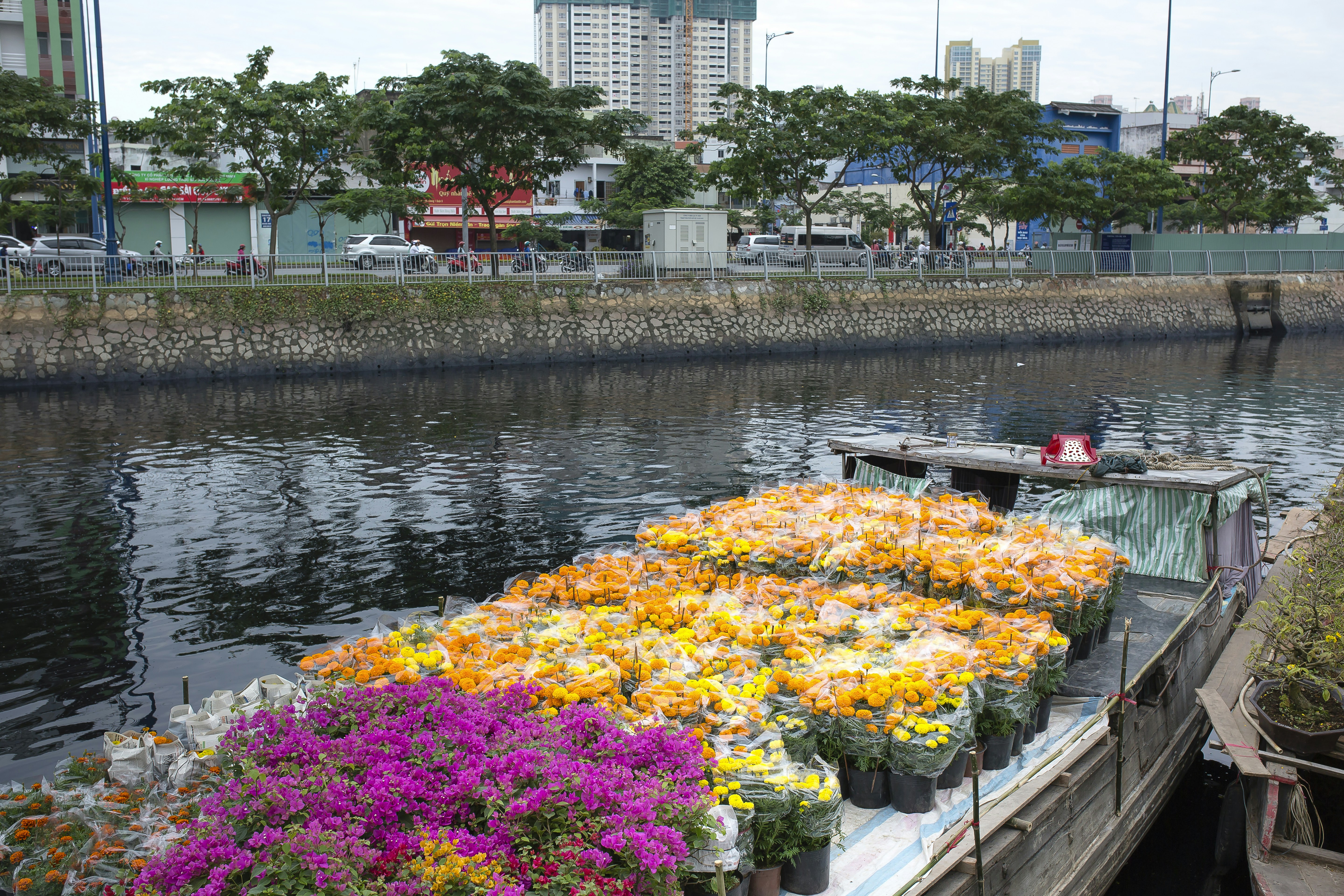 a boat filled with lots of flowers floating on top of a river
