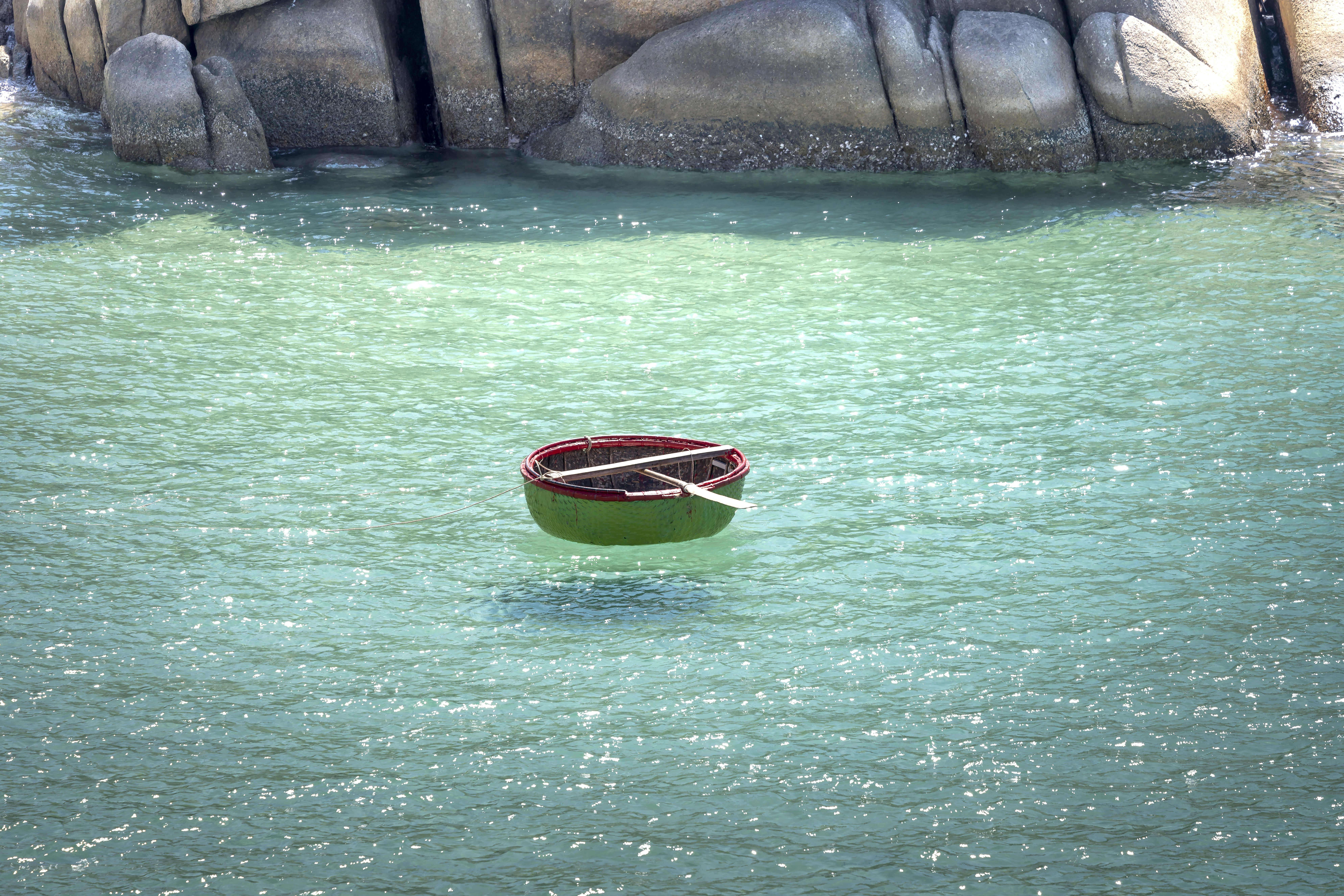 Jade Ring Buoy Adrift in Turquoise Water by a Granite Shore