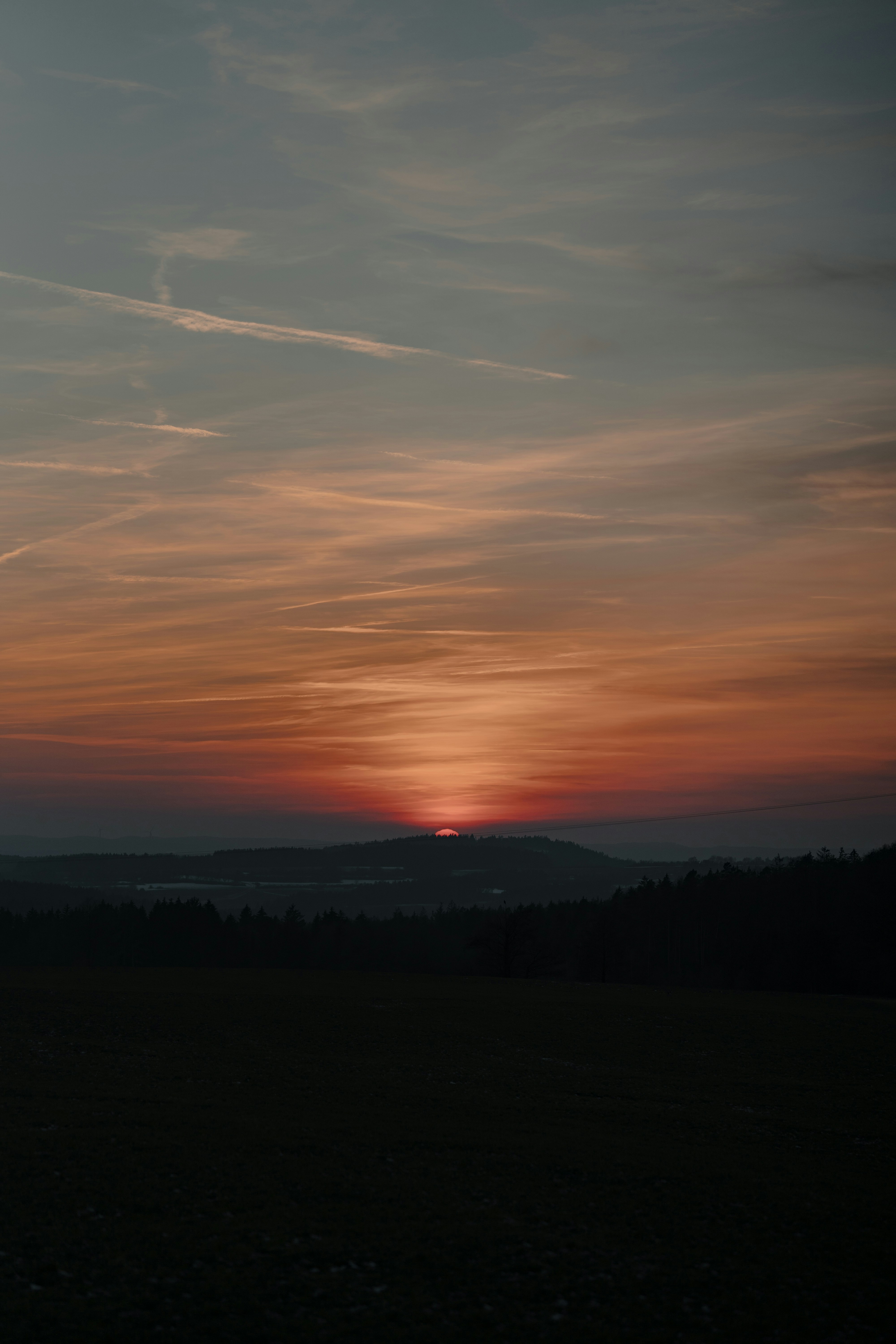 Sunset over distant hills with vibrant orange and pink hues in the sky.