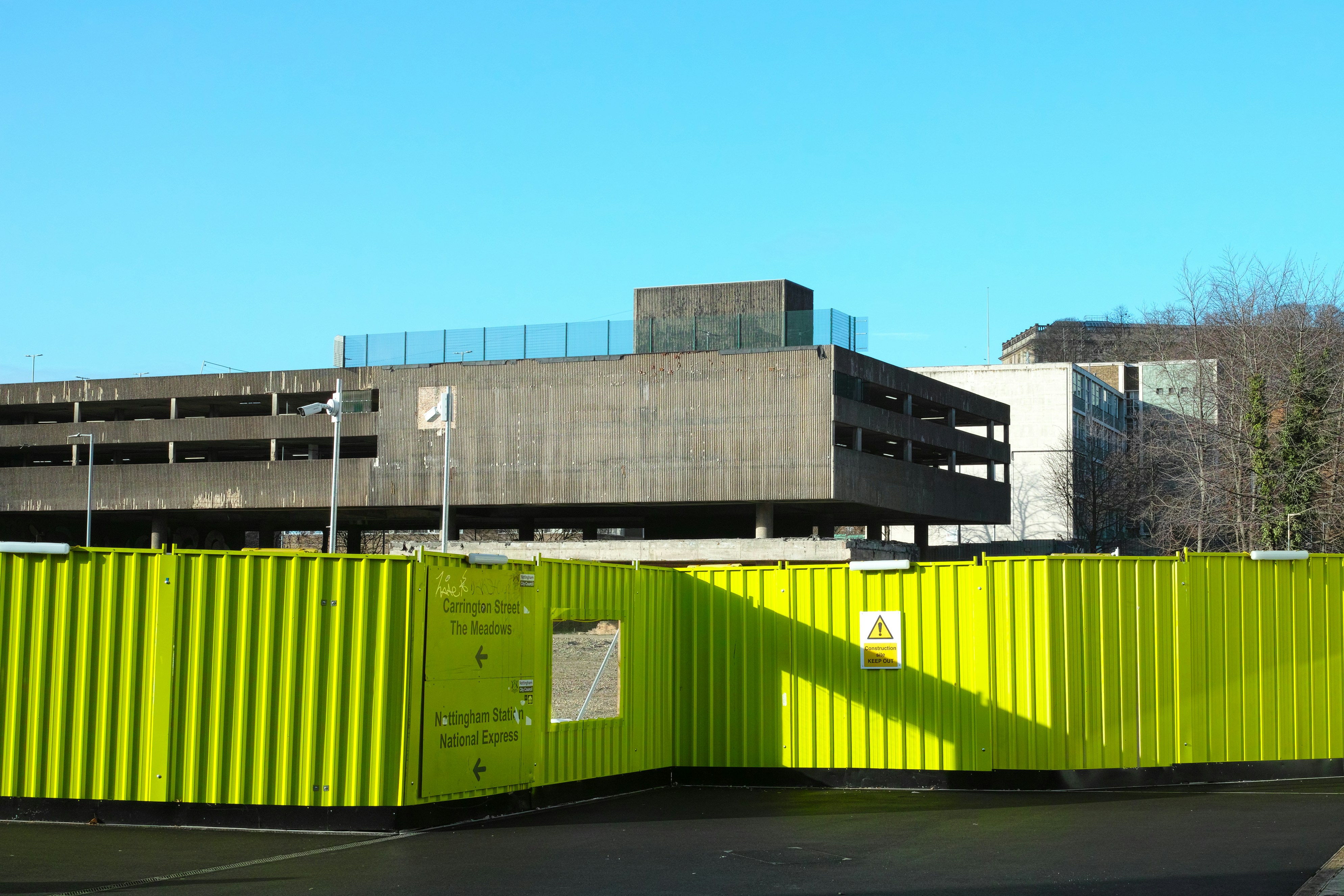 A striking contrast between a gray concrete structure and vibrant yellow construction barriers under a clear blue sky.
