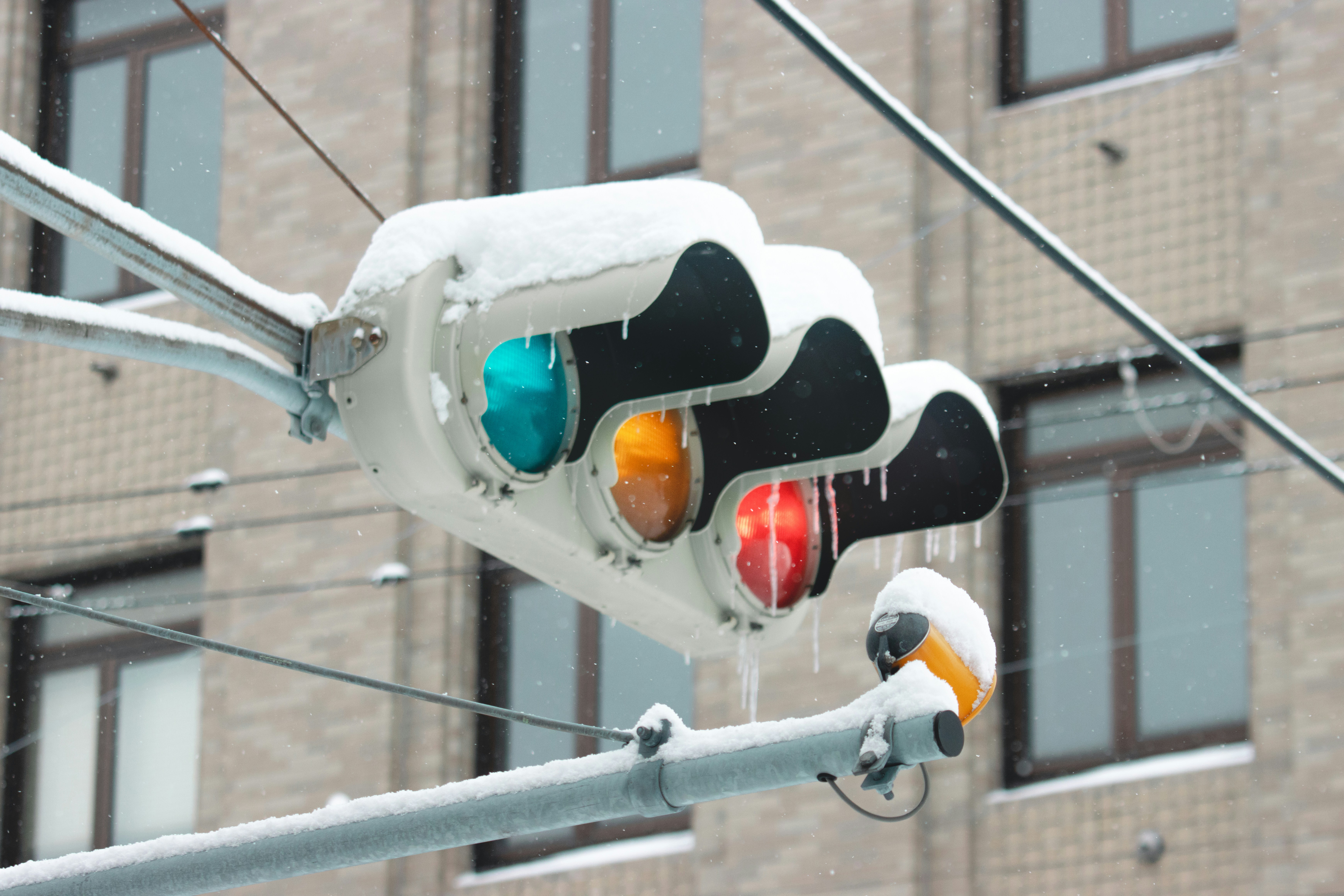 A traffic light covered in snow next to a building photo – Free Traffic ...