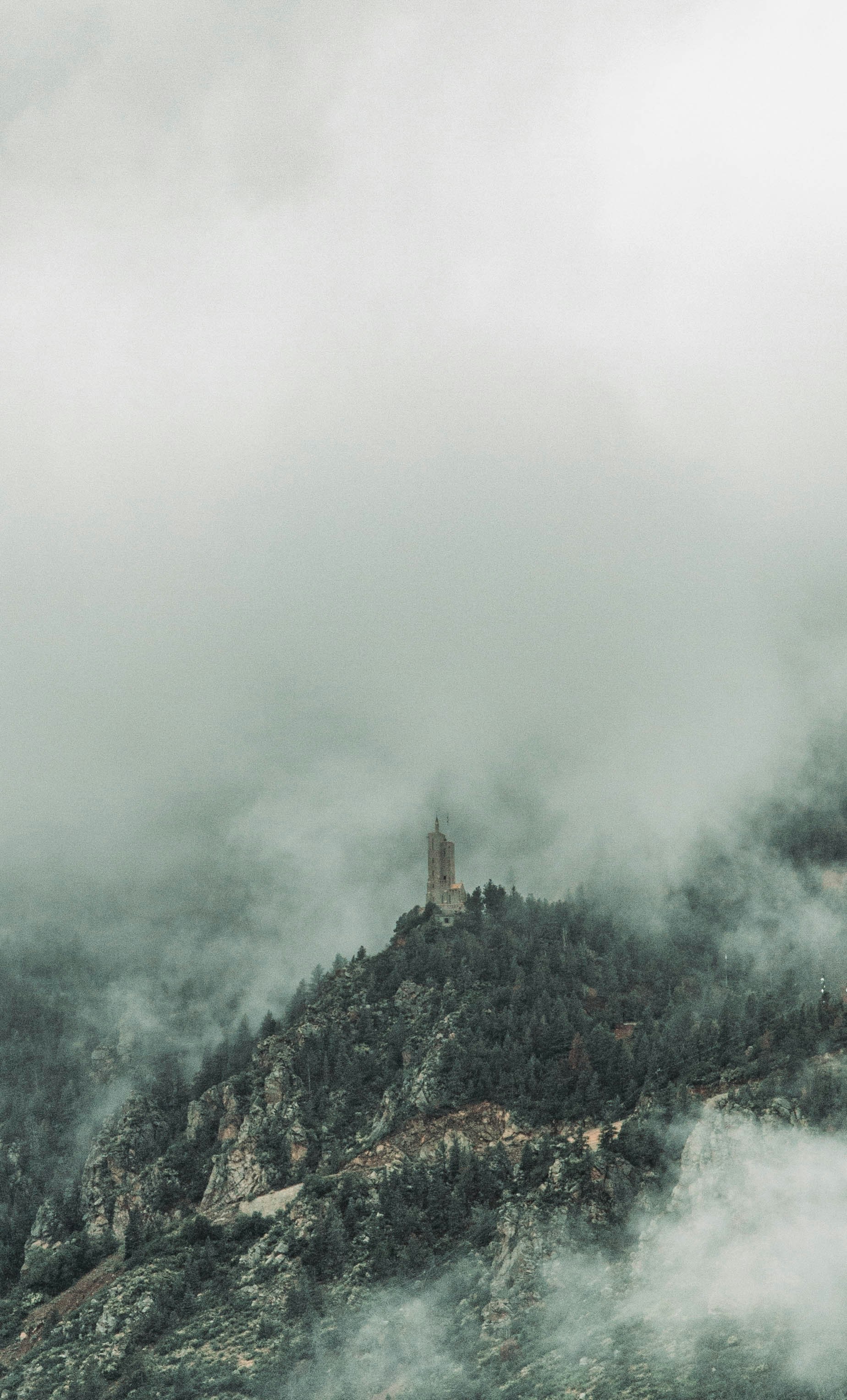 A mountain covered in fog with a clock tower in the distance photo ...