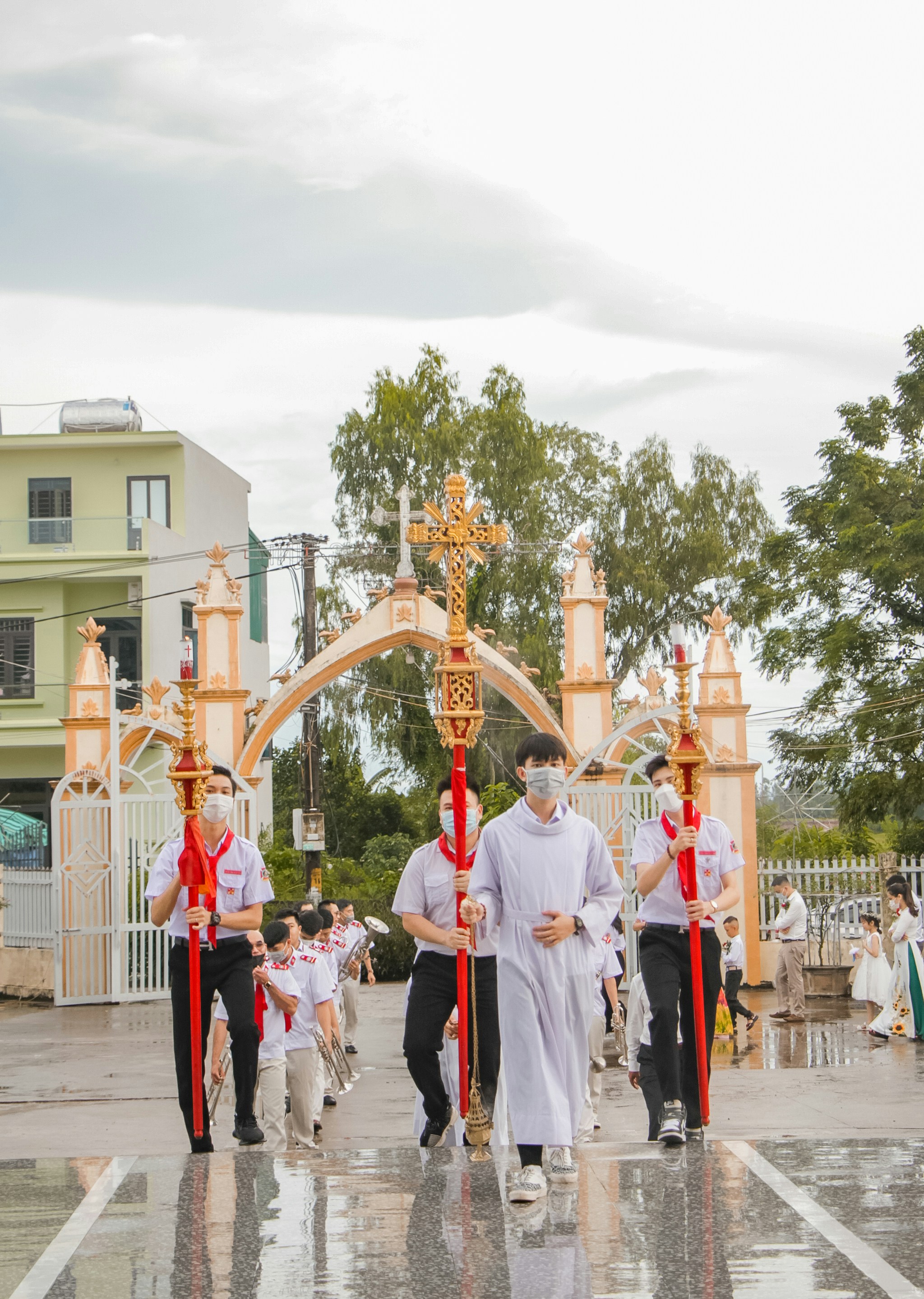 Procession of liturgical banners in a sunlit courtyard