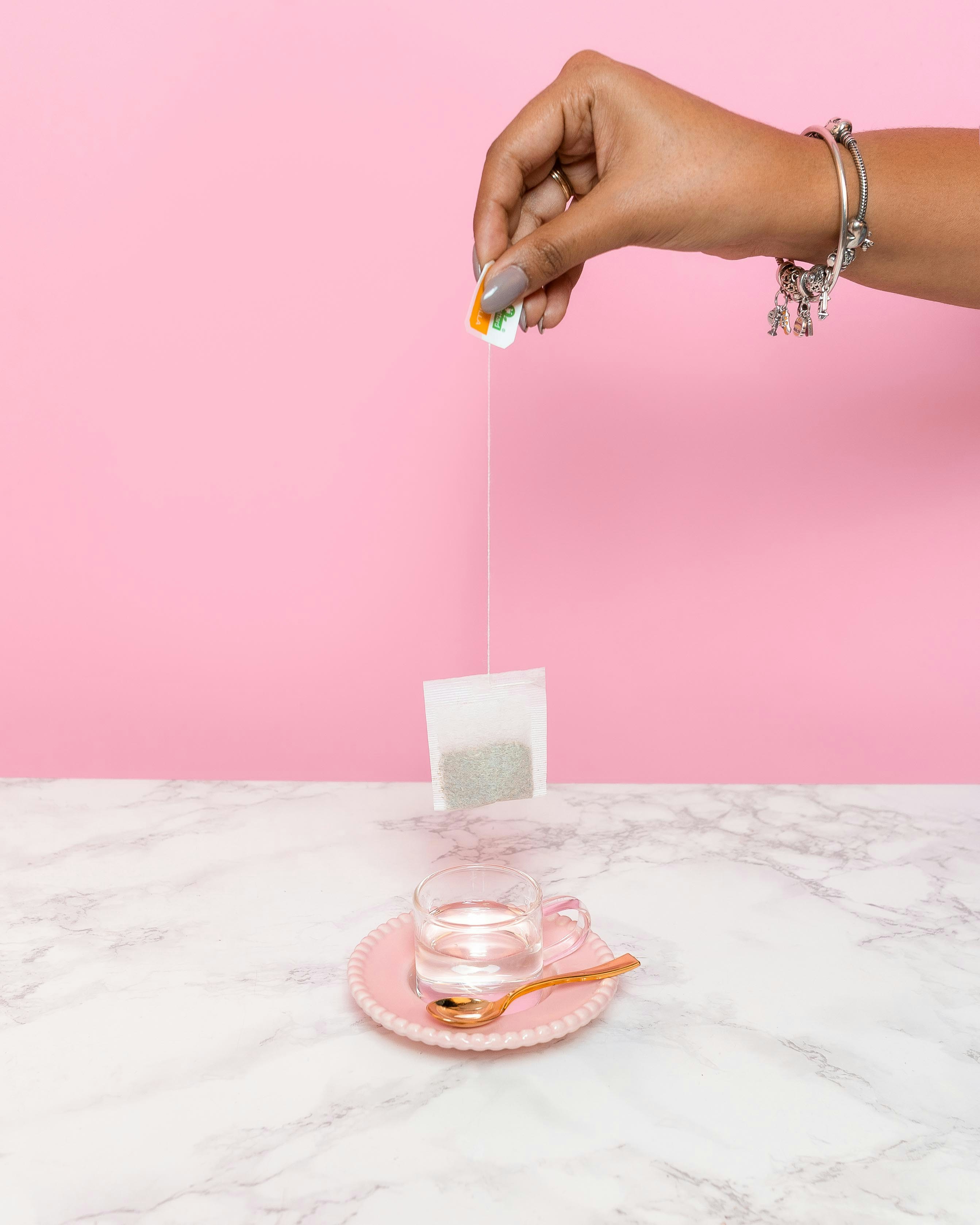 Rosy Minimalism: A Hand Dips Tea Bag into Water on Marble