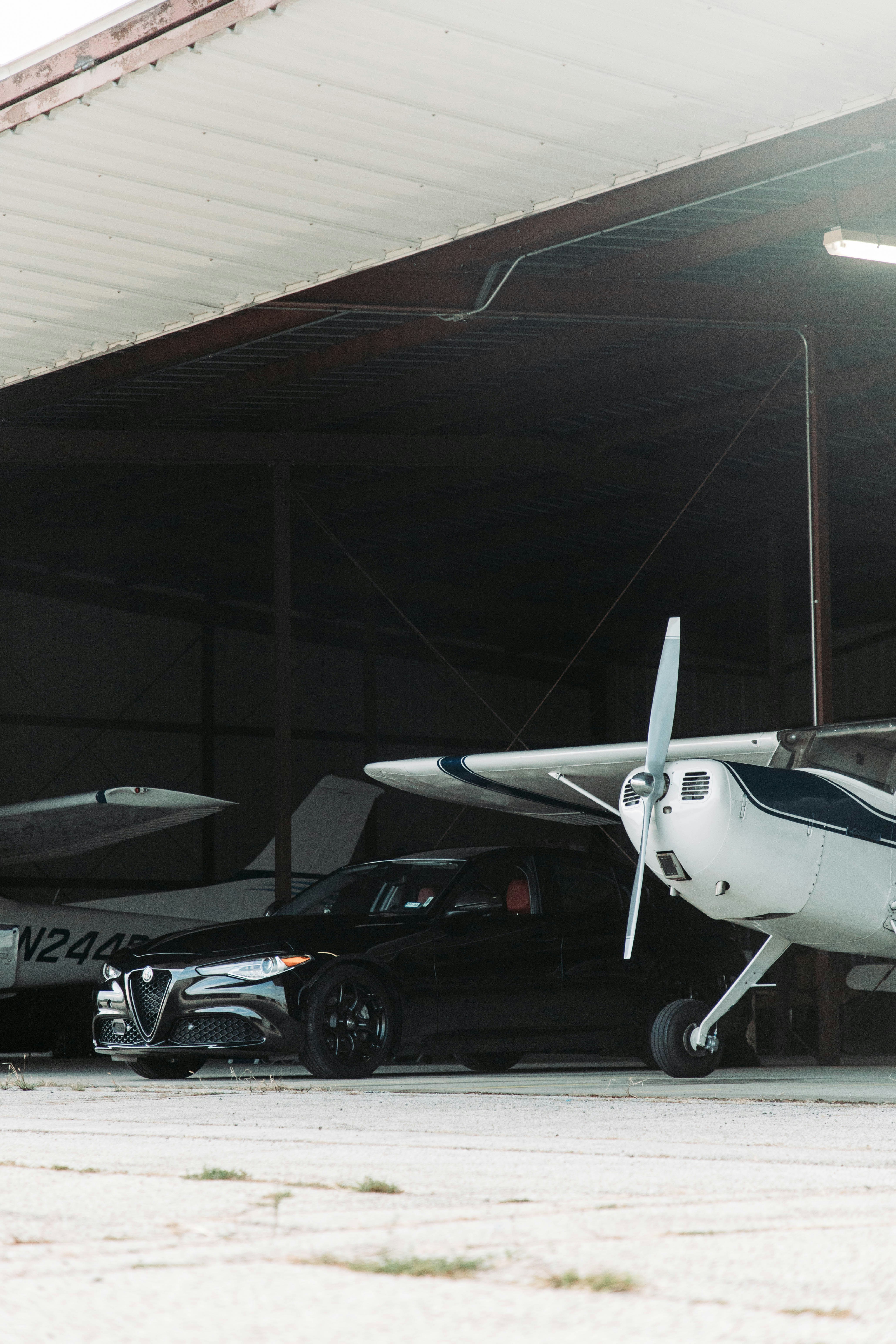 A small airplane parked in a garage next to a car photo – Free Purdue ...
