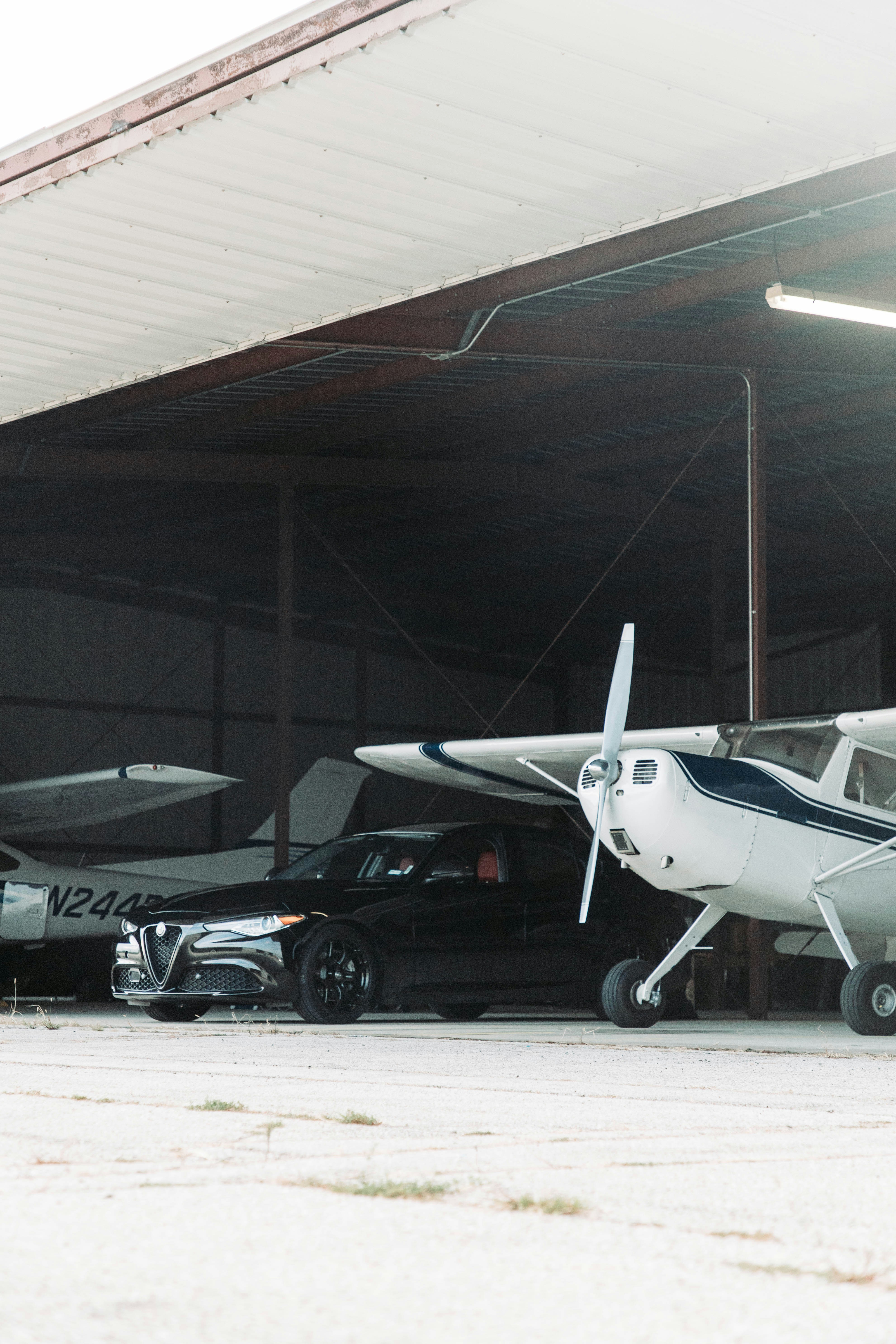 A small airplane parked in a garage next to a car photo – Free Cars ...