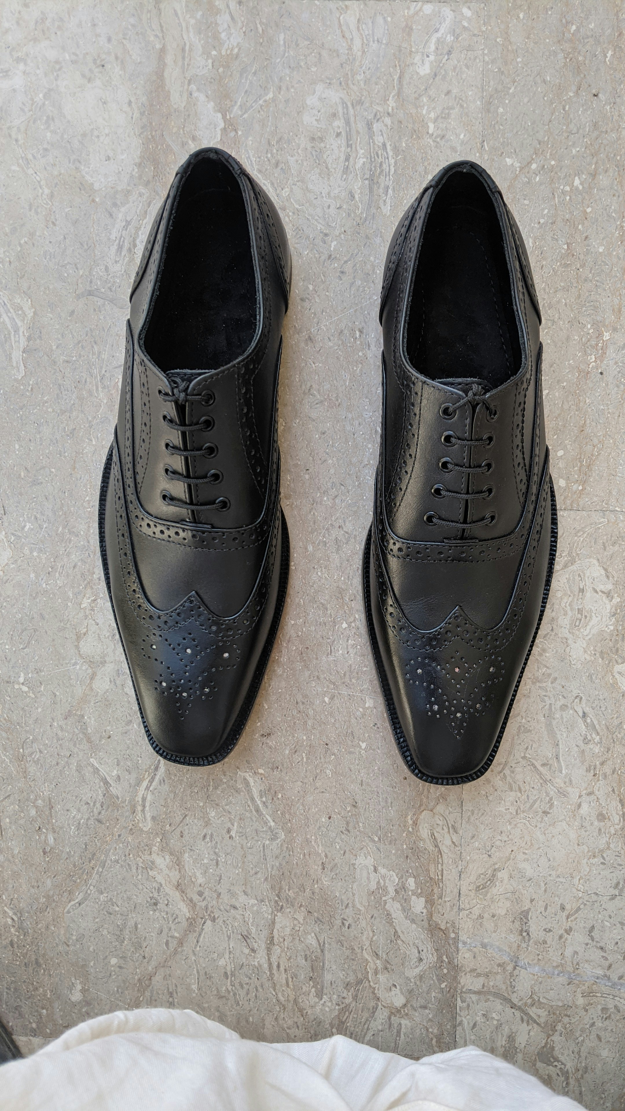 a pair of black shoes sitting on top of a marble floor