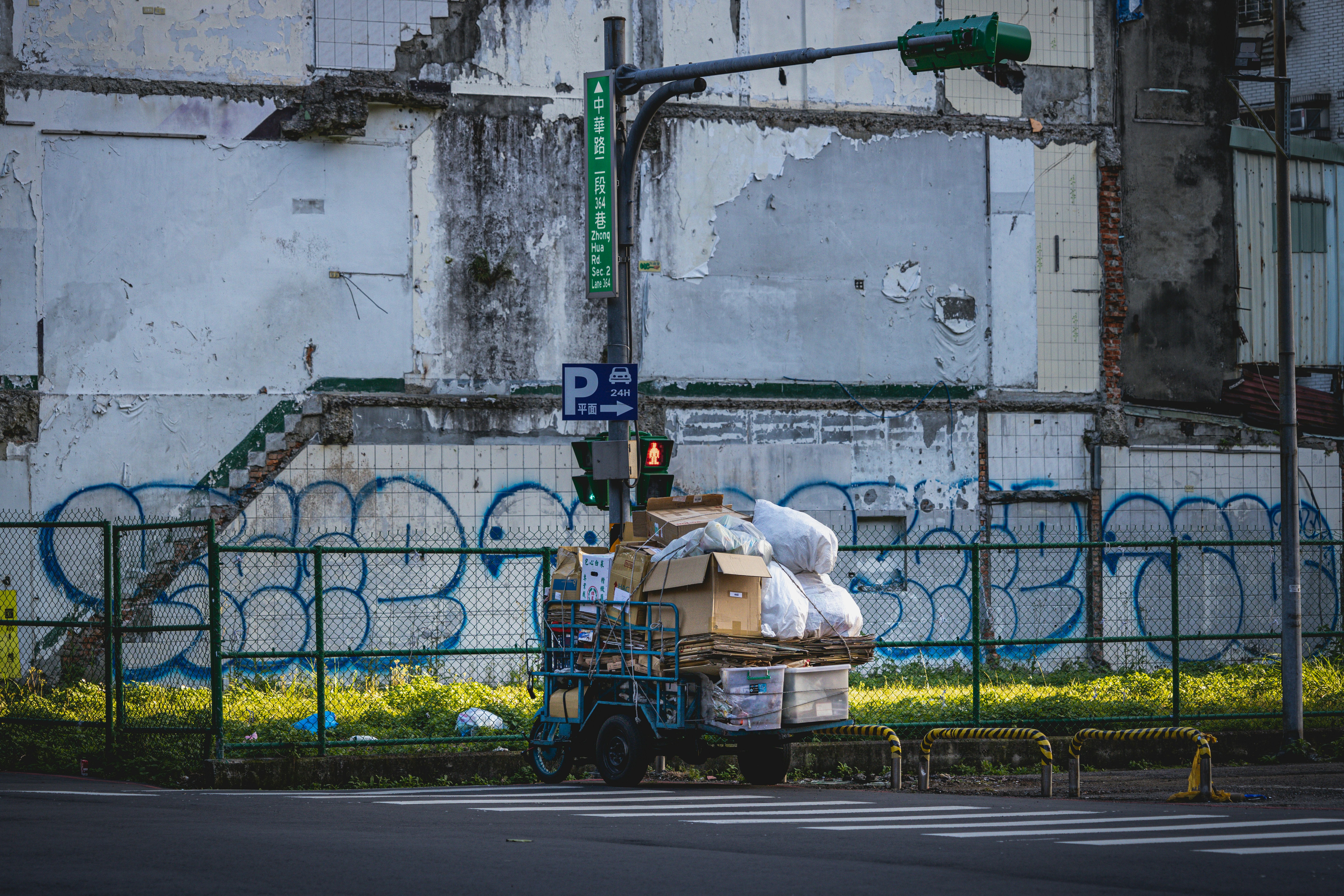 Street-side Stowaway: A Cart Laden with Bags Against a Graffitied Wall