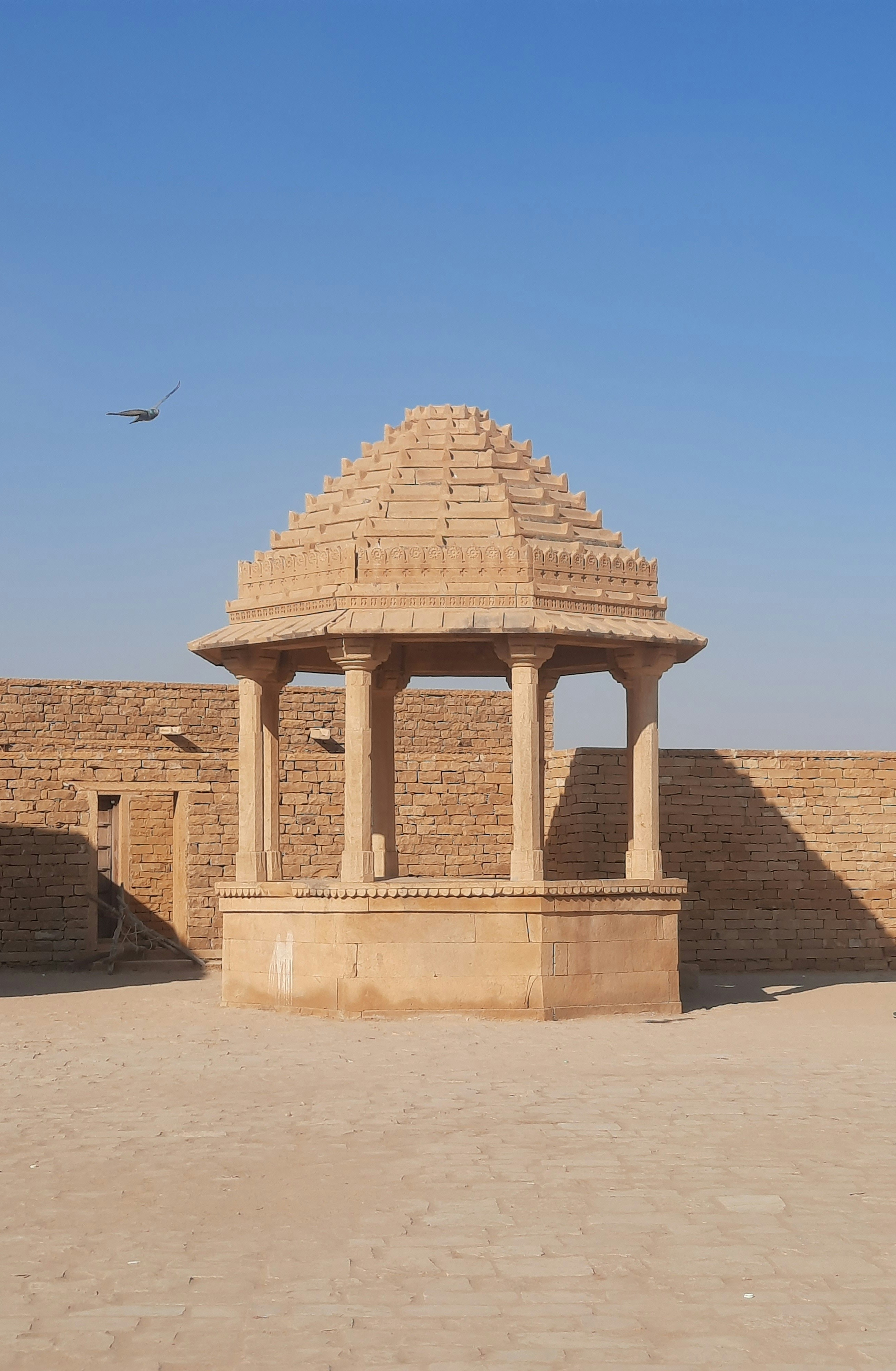 Desert Tiered Pavilion Rising from Sandstone Walls Under a Clear Blue Sky