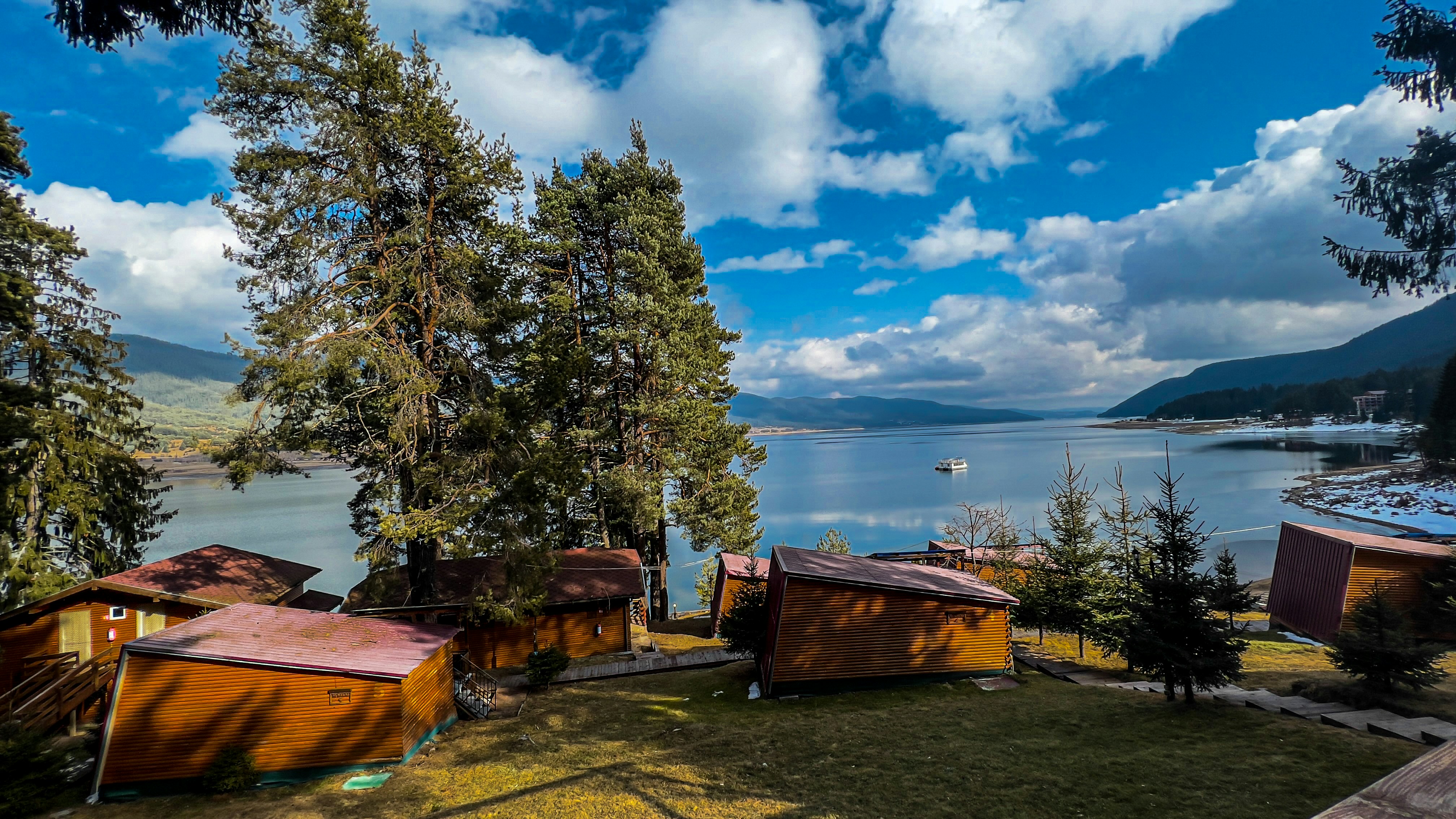 A group of wooden cabins sitting on top of a lush green hillside photo ...