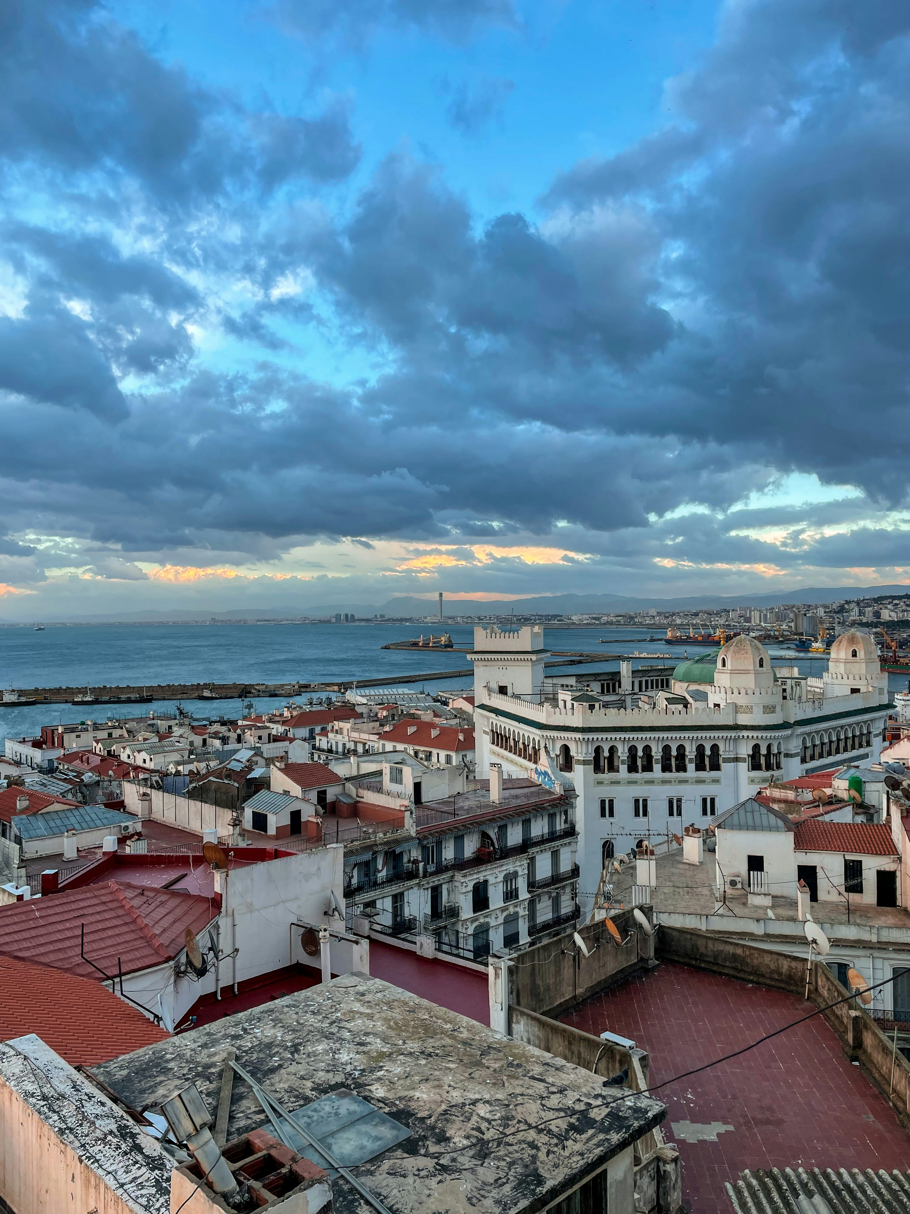 White-Domed Towers Over Red-Tiled Rooftops at Dusk Along the Coastal Panorama