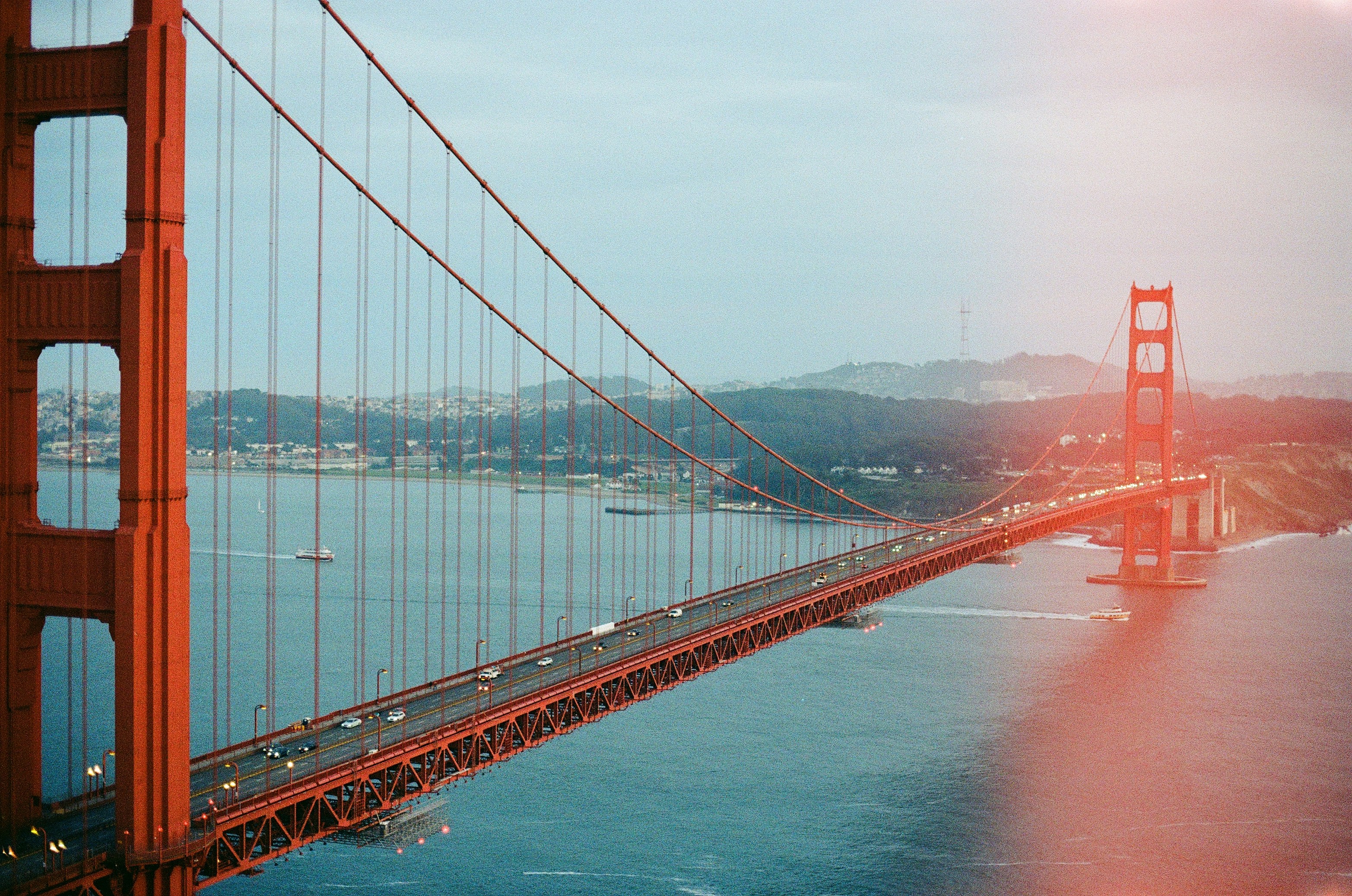 Iconic Golden Gate Bridge spanning the bay, framed by a serene coastal landscape at dusk.