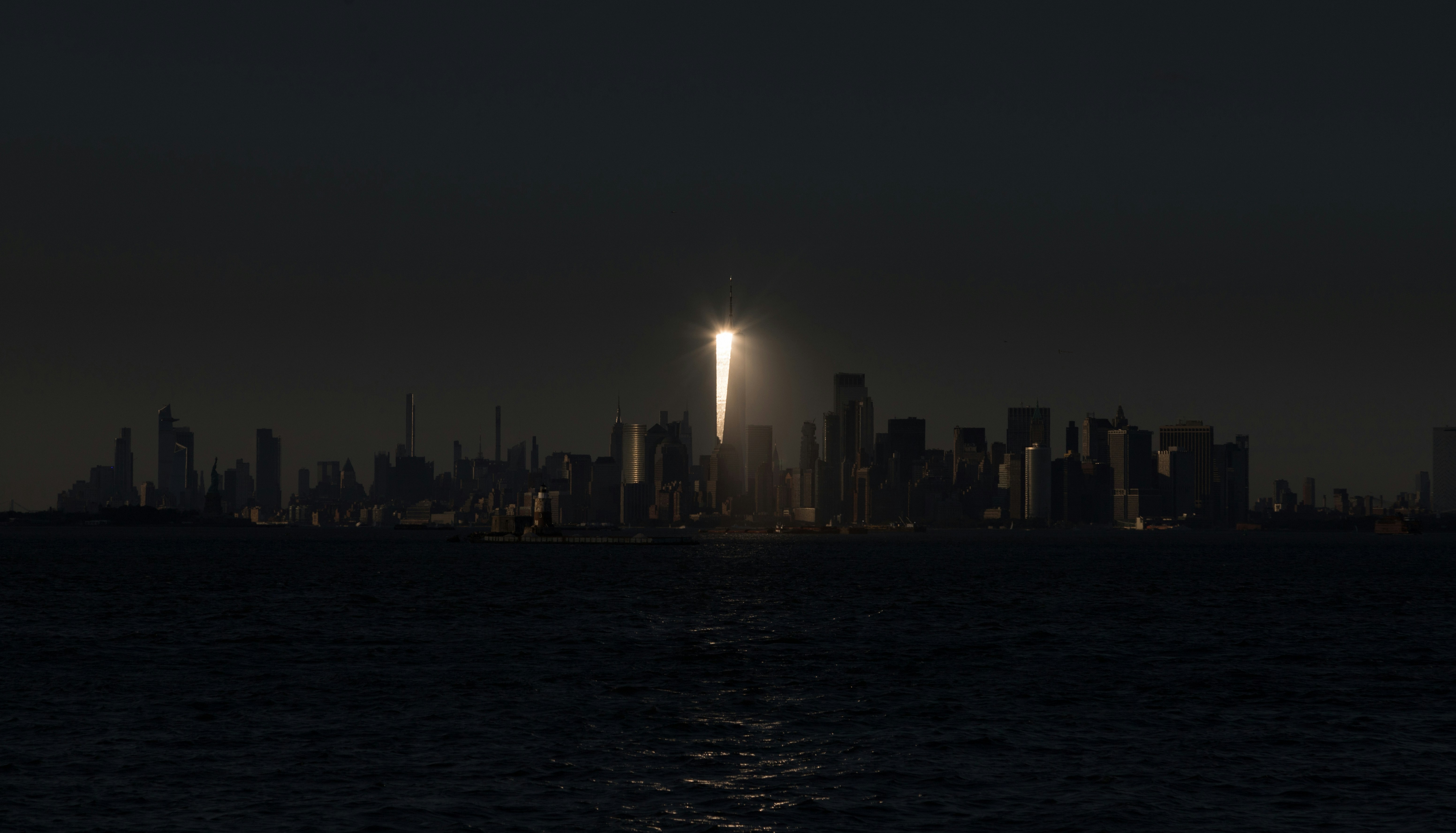 a city skyline at night with a bright light in the sky