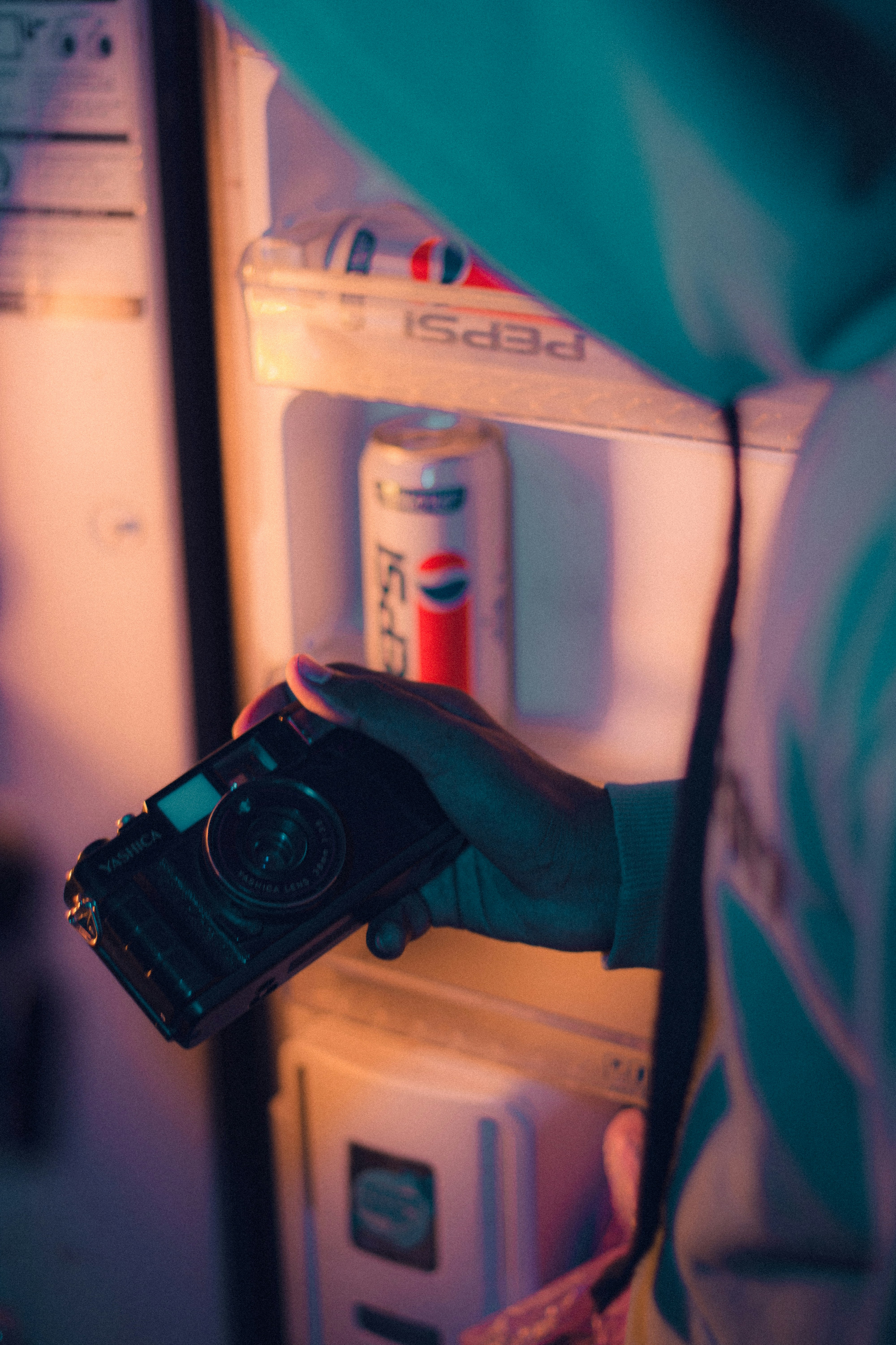 a person holding a camera in front of an open refrigerator