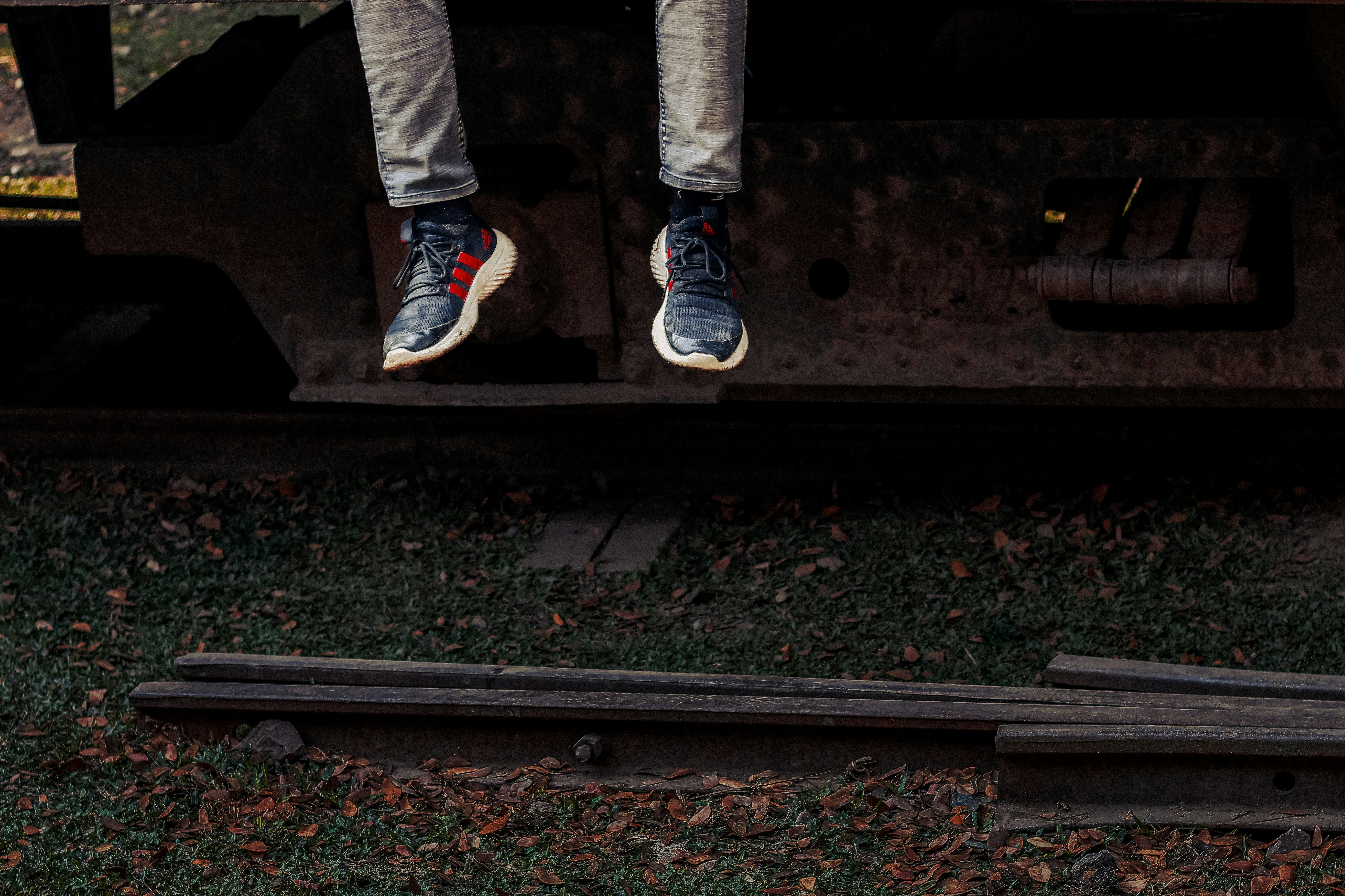 Edge of the Car: Blue Sneakers Hover Over Weathered Rails