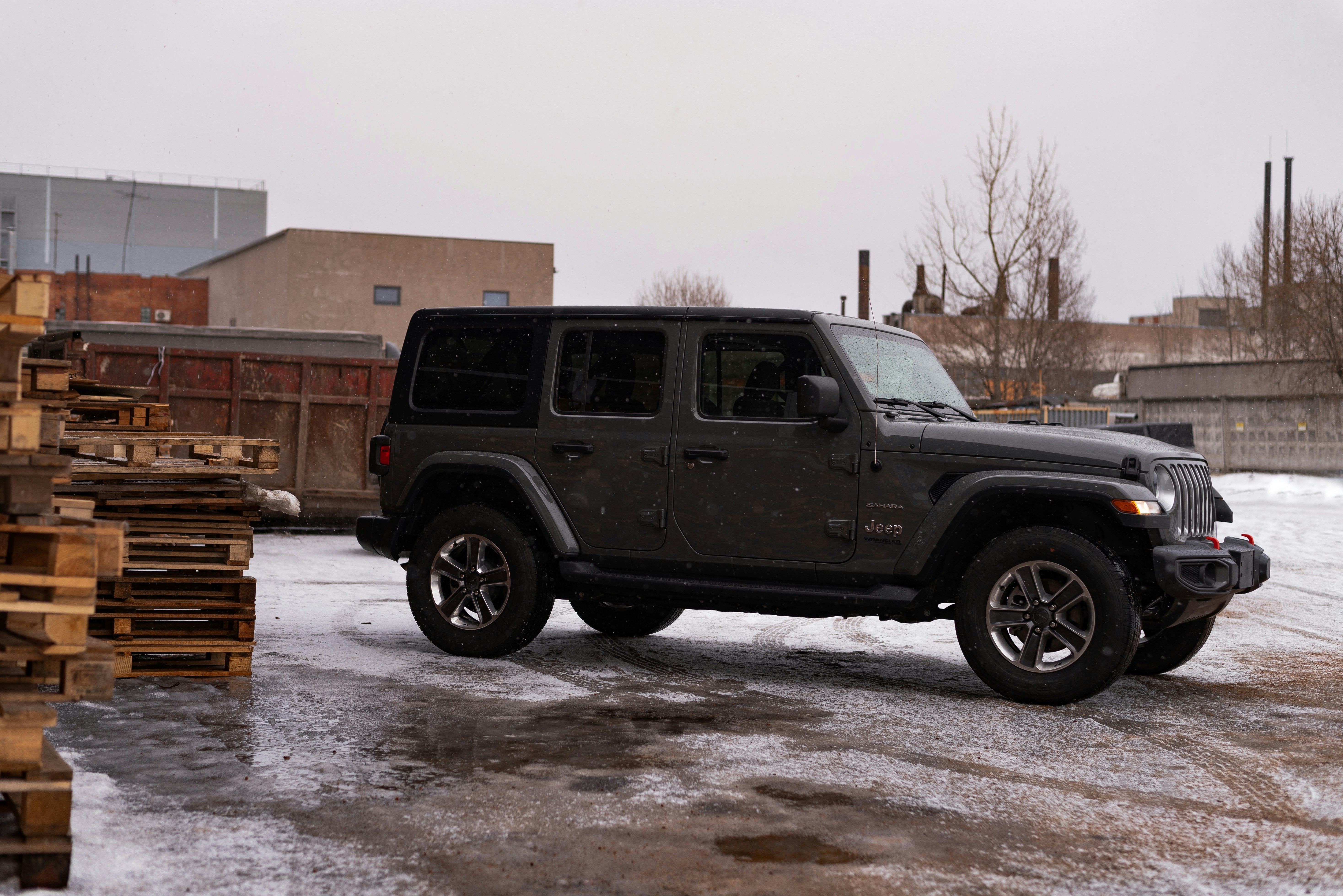 Midwinter Yard Standoff: Jeep Wrangler on a Rain-Slick Industrial Lot