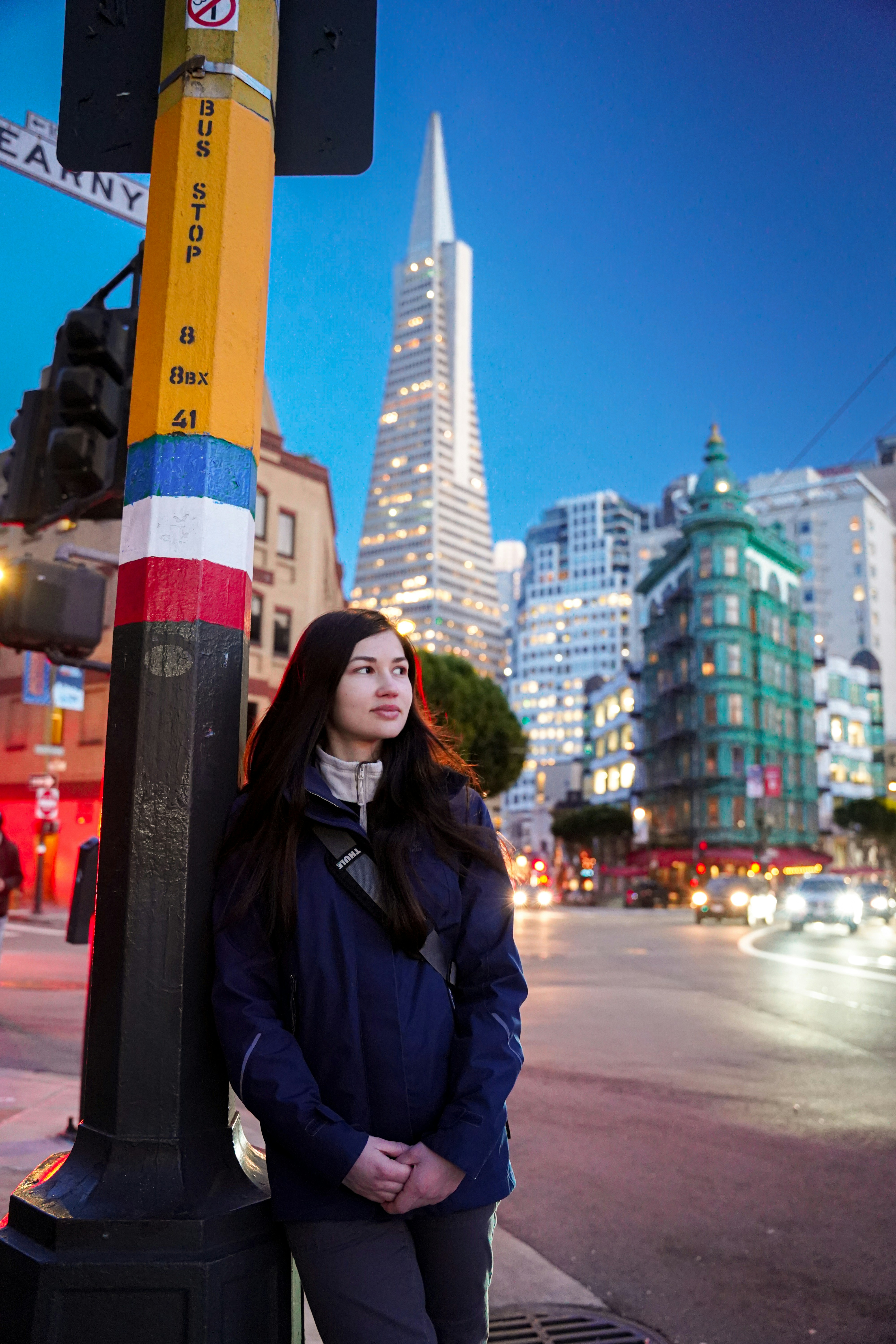 A woman leaning against a pole on a city street photo – Free San ...