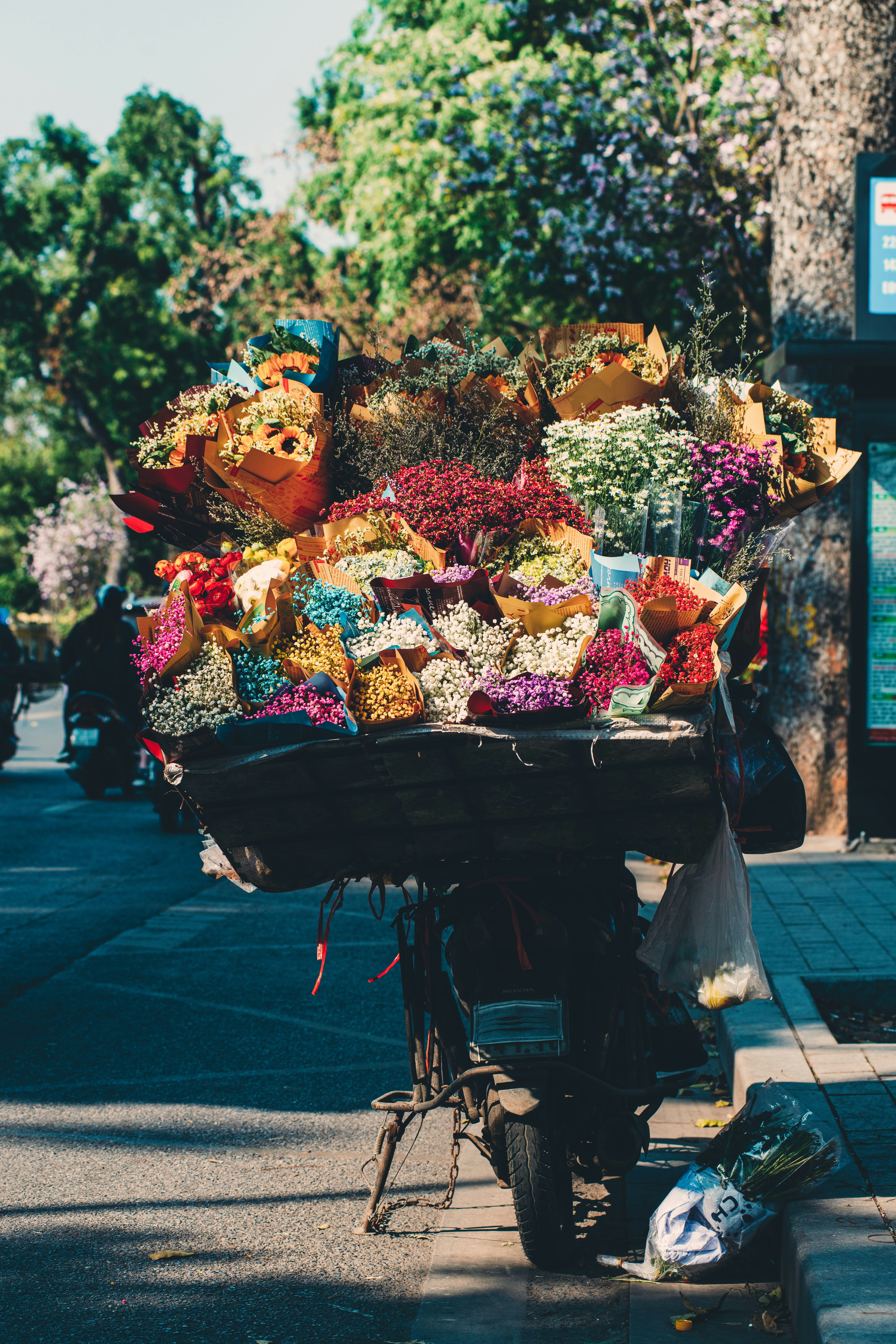 a cart full of flowers sitting on the side of a road
