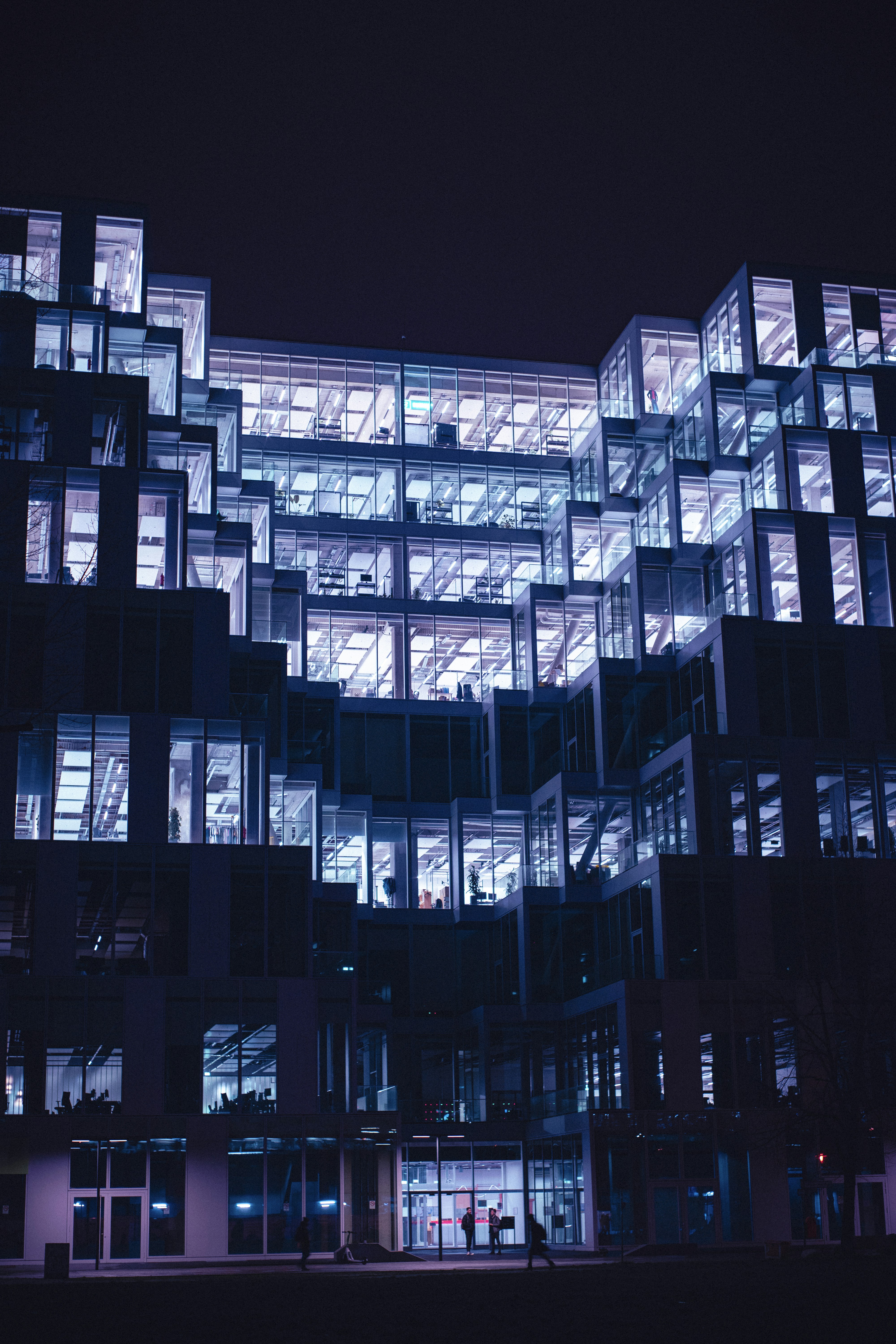 A building with many windows lit up at night photo – Free Berlin Image ...