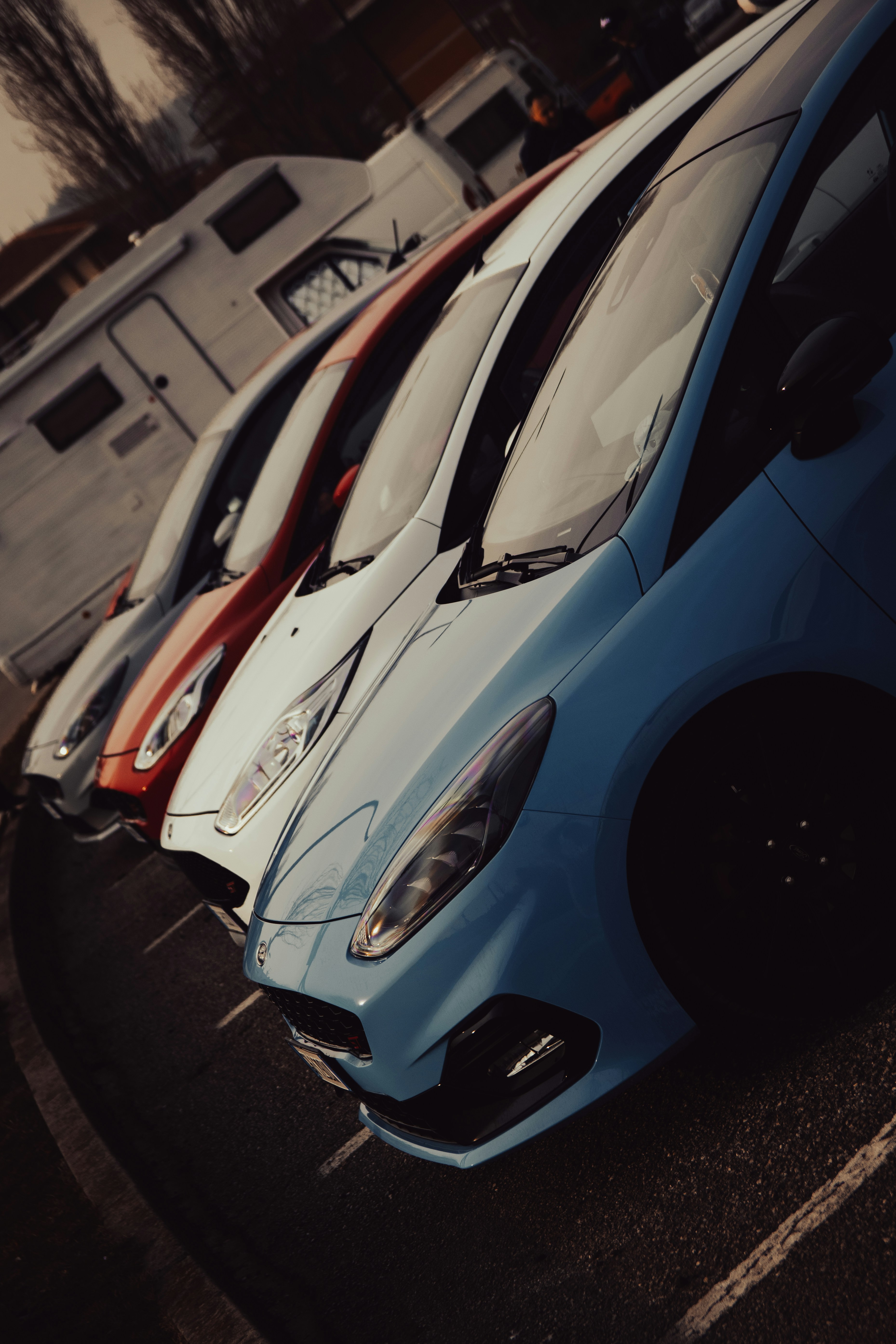 Diagonal Rainbow: A glossy lineup of hatchbacks in parking-lot light