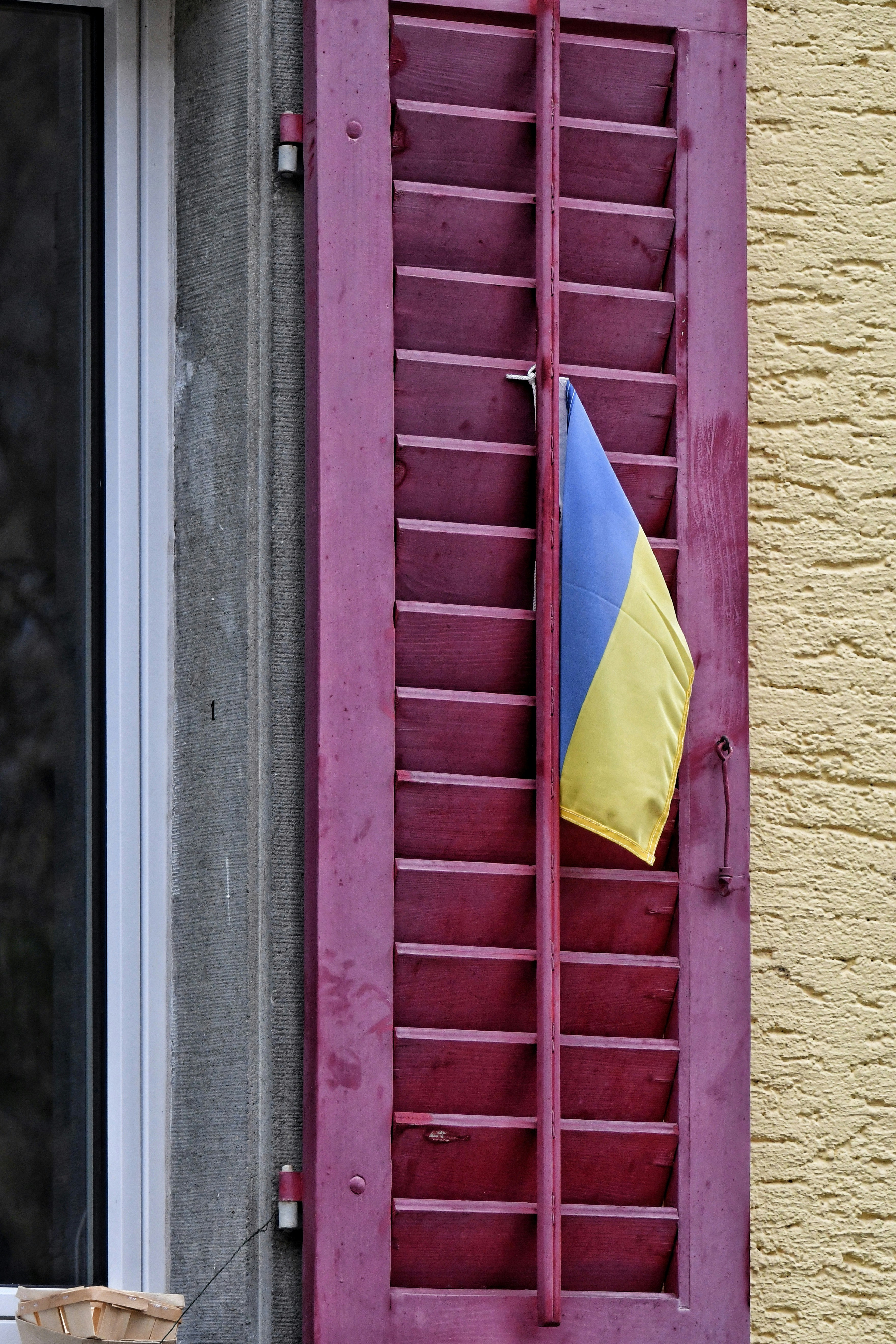 A flag hanging on a window sill next to a basket photo – Free Wipkingen ...
