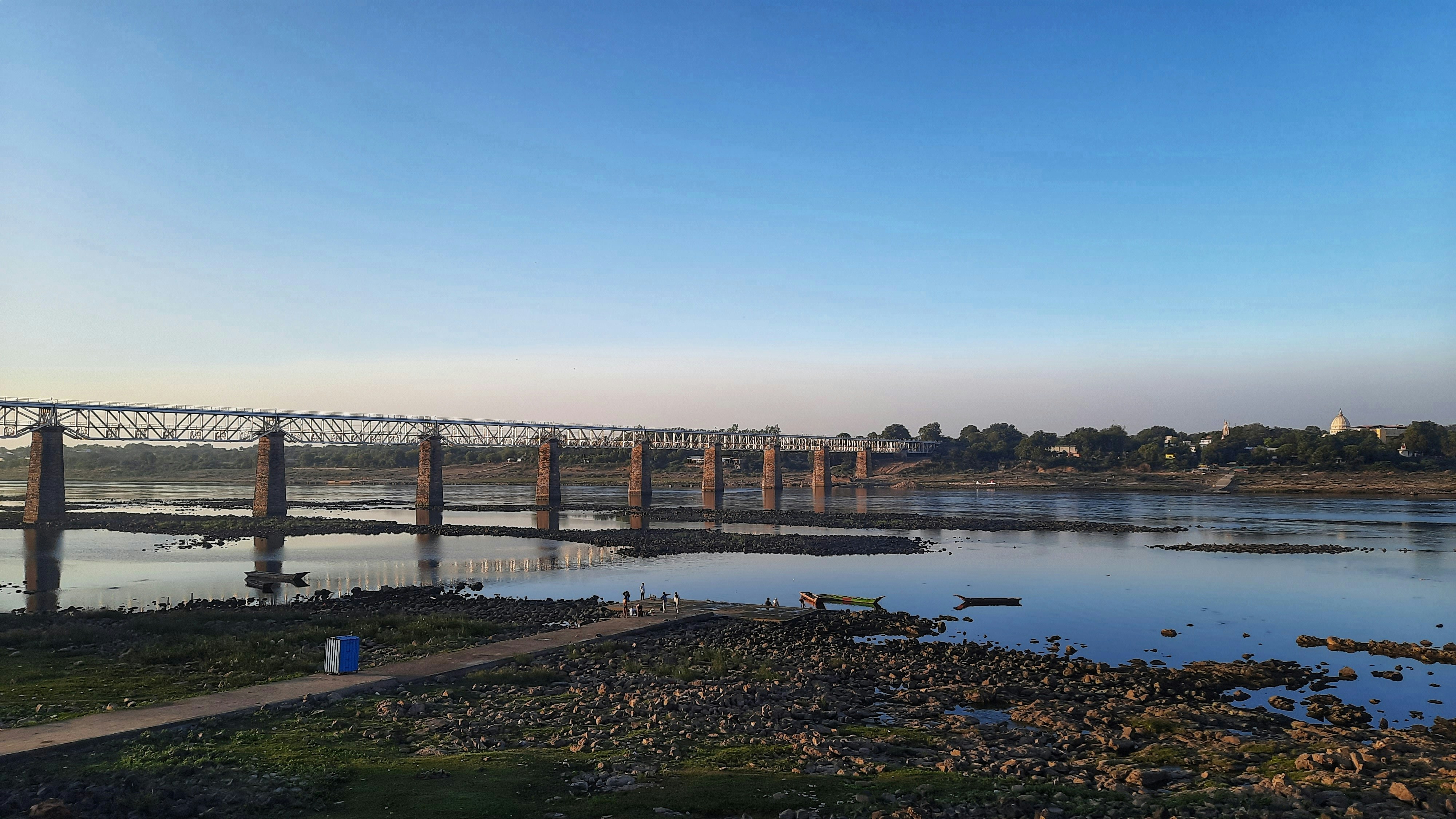 Old railway bridge spanning the Narmada River under a clear blue sky.