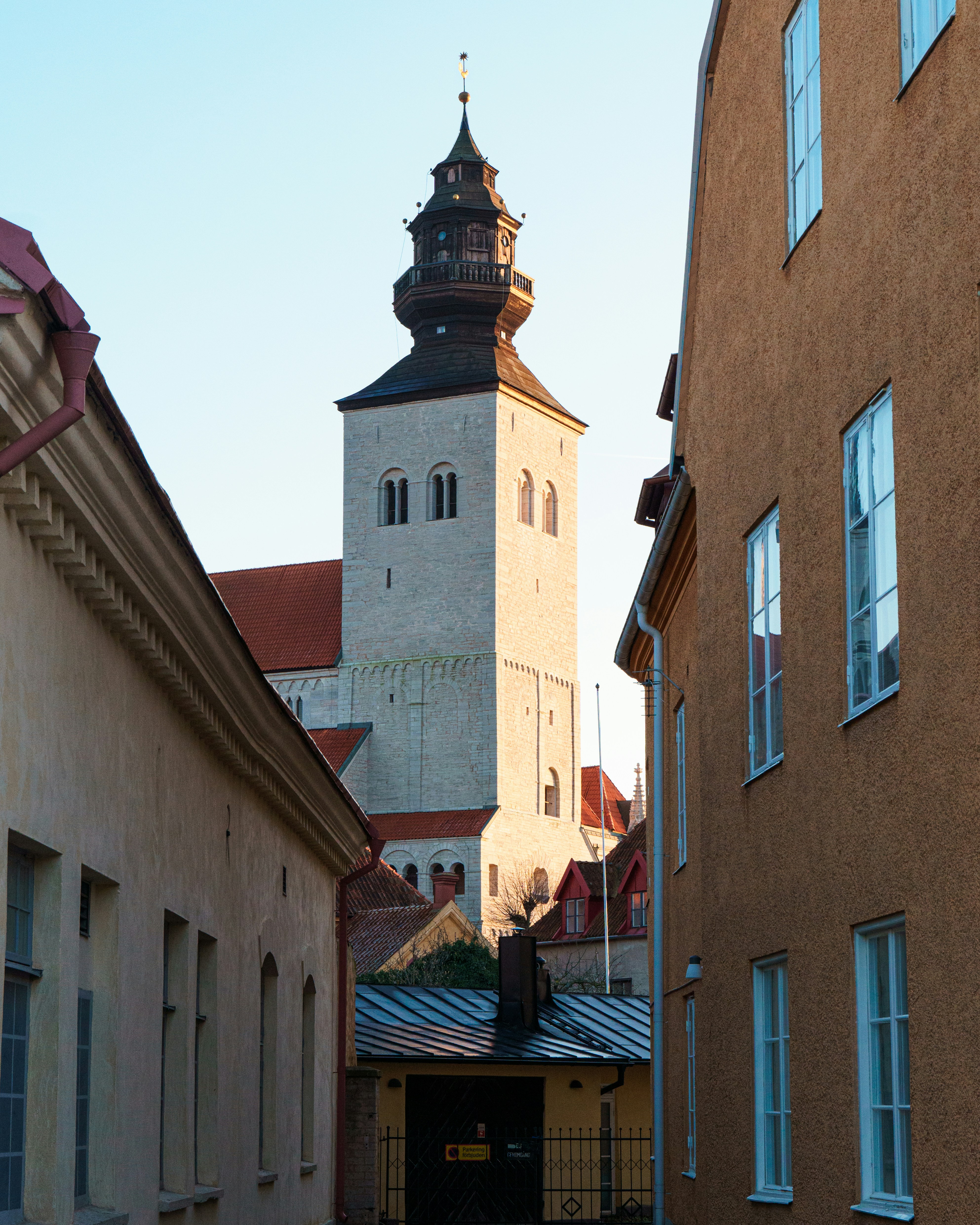 Visby cathedral photographed from one of the charming alleys surrounding it. This 13th-century cathedral the only medieval church in Visby that is still being used today, not succumbing to the same fate of ruination like 13 other churches in the small town. | a tall building with a clock on the top of it