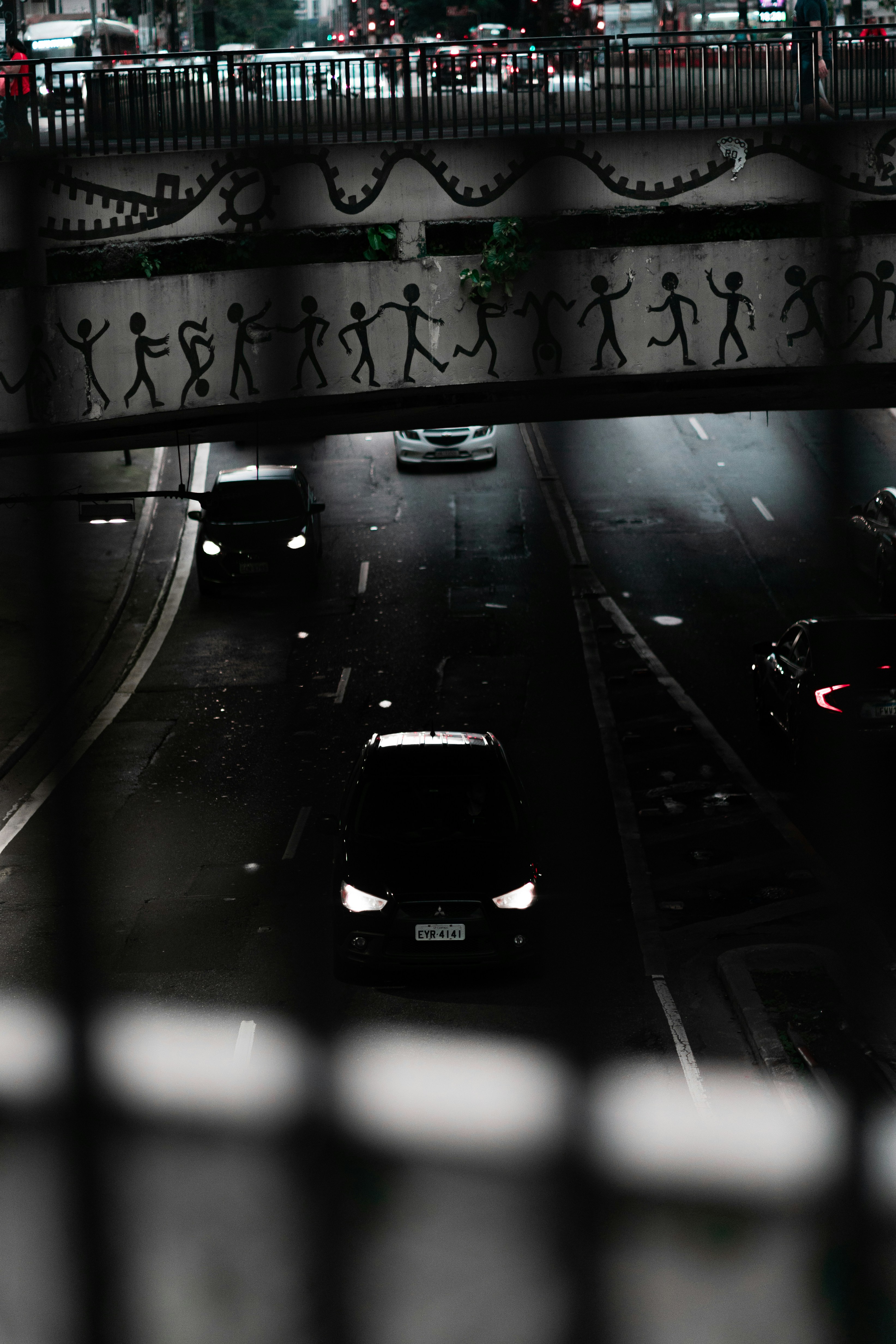 a city street filled with lots of traffic under a bridge