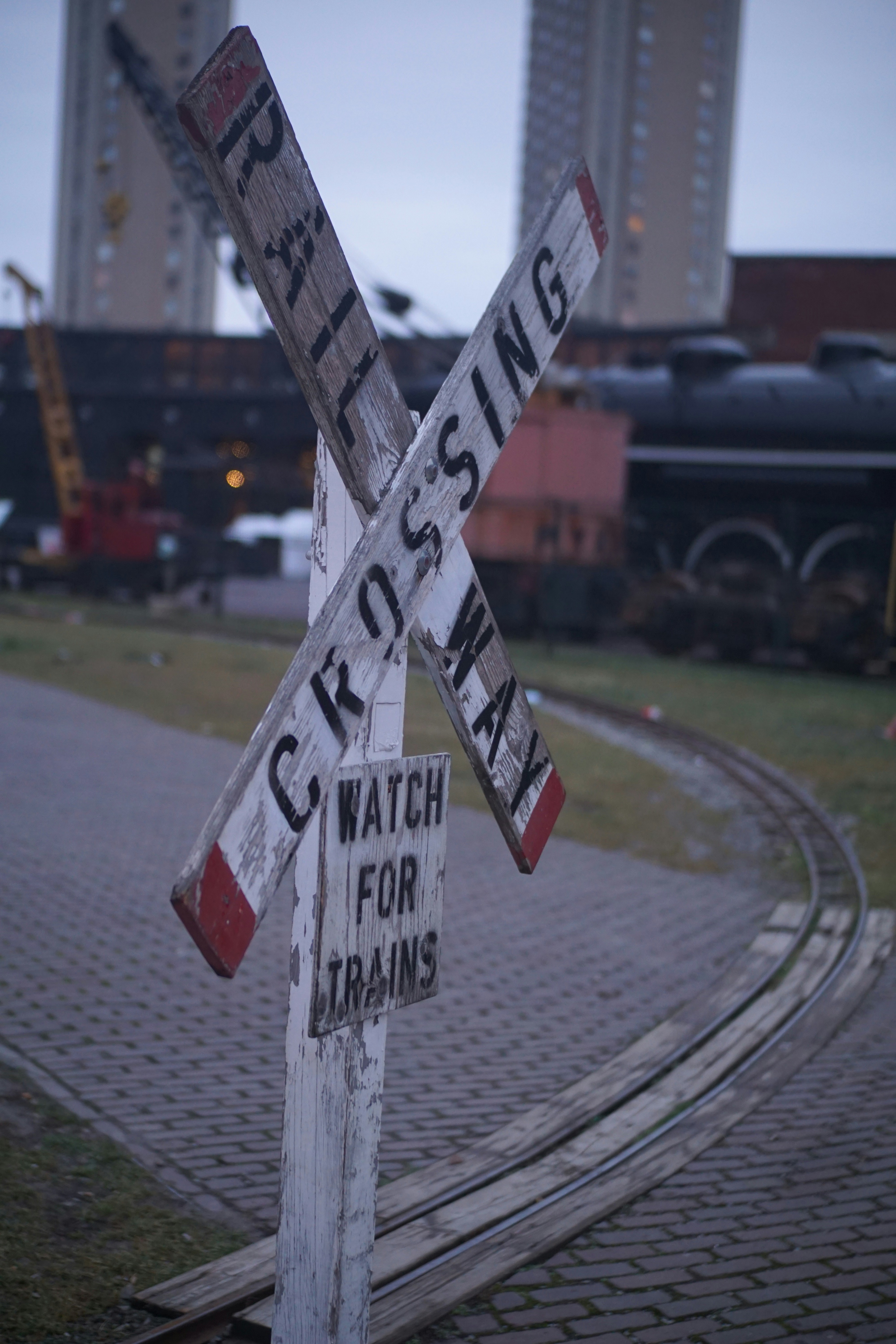 Weathered Railroad Crossing Sign Framed by a Curving Urban Track
