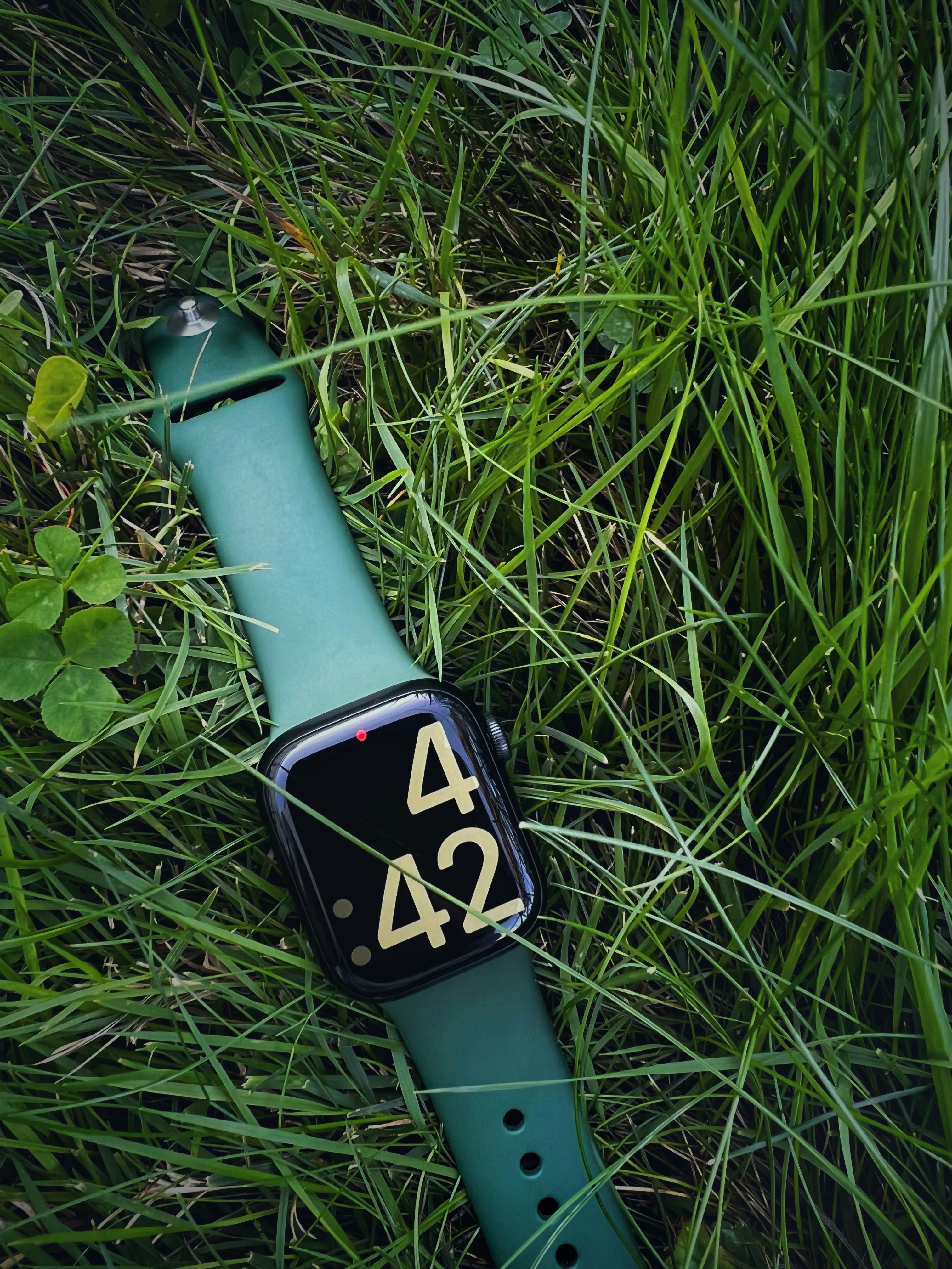 a green apple watch sitting in the grass